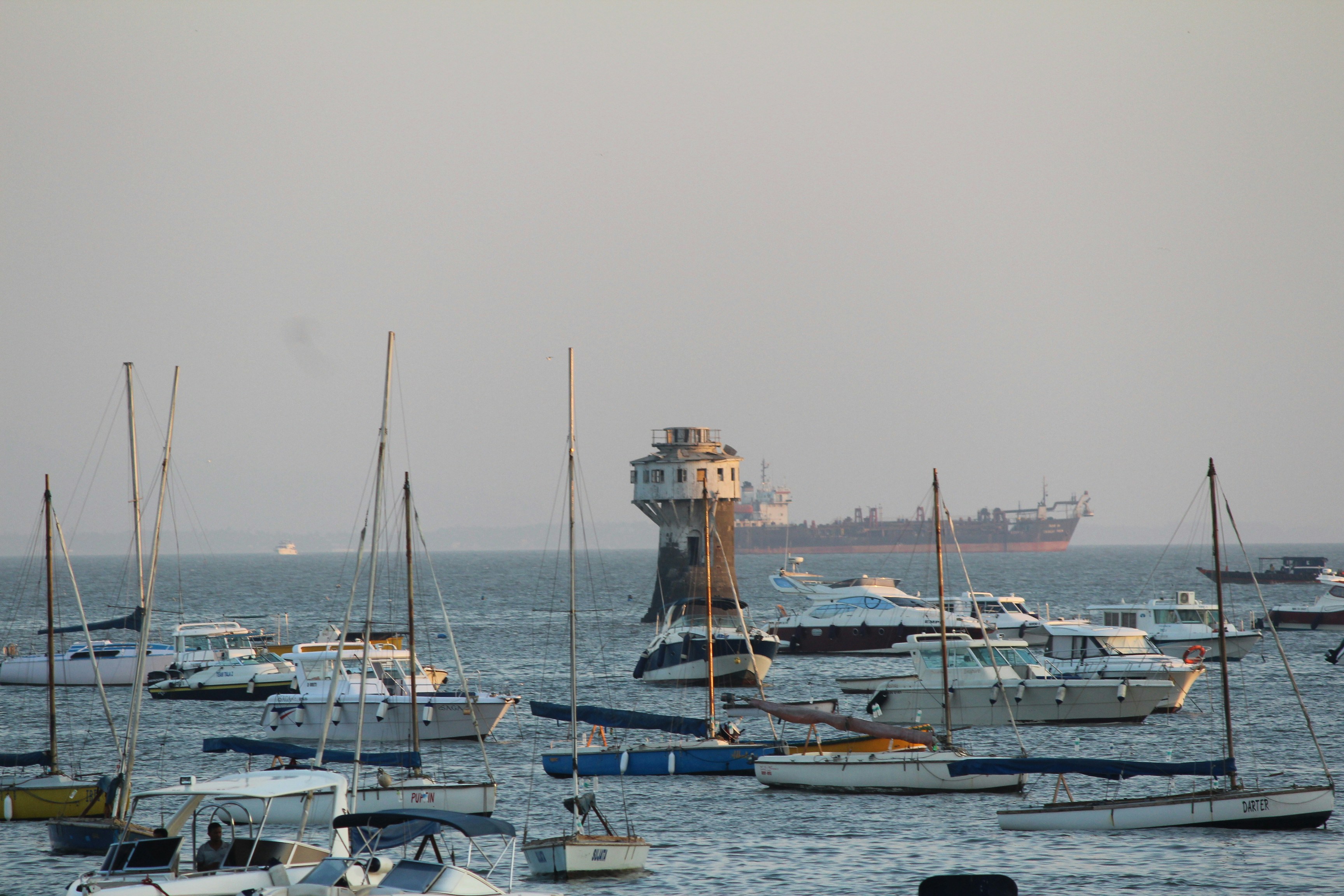 Boats and a tower dot a tranquil seascape.