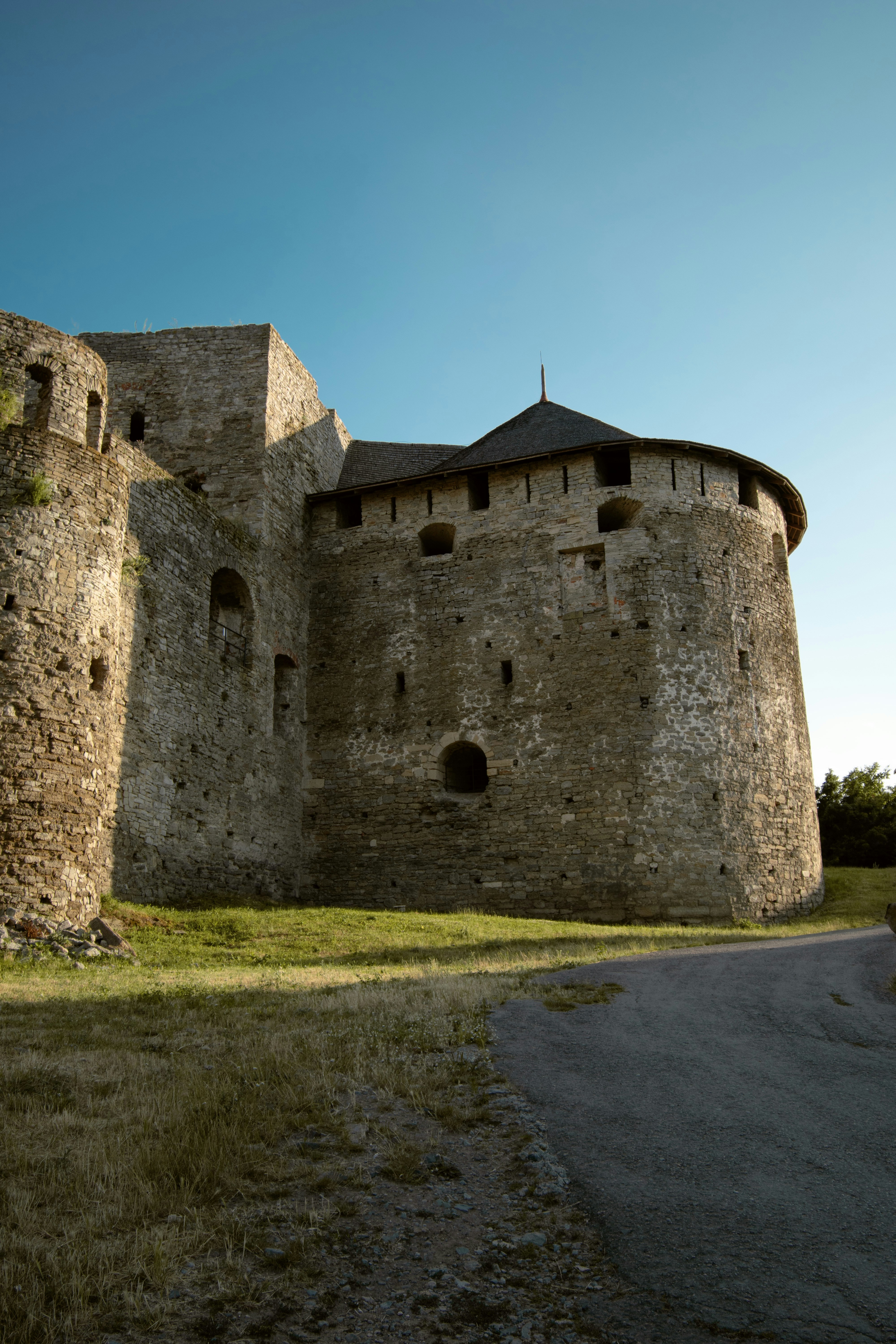 An ancient stone castle stands tall under a blue sky.