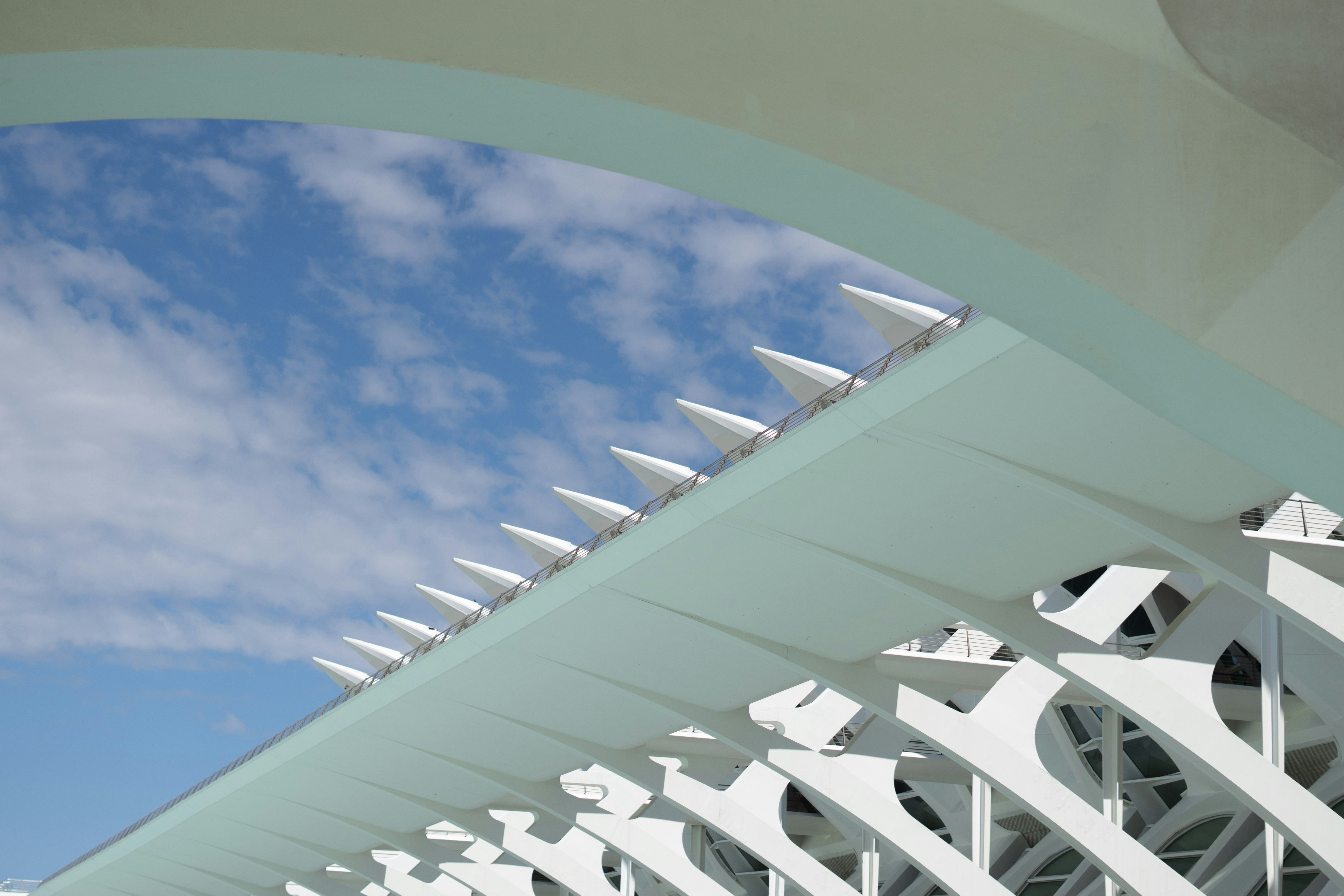 A modern architectural structure with sharp, angular lines contrasting against a blue sky dotted with clouds.