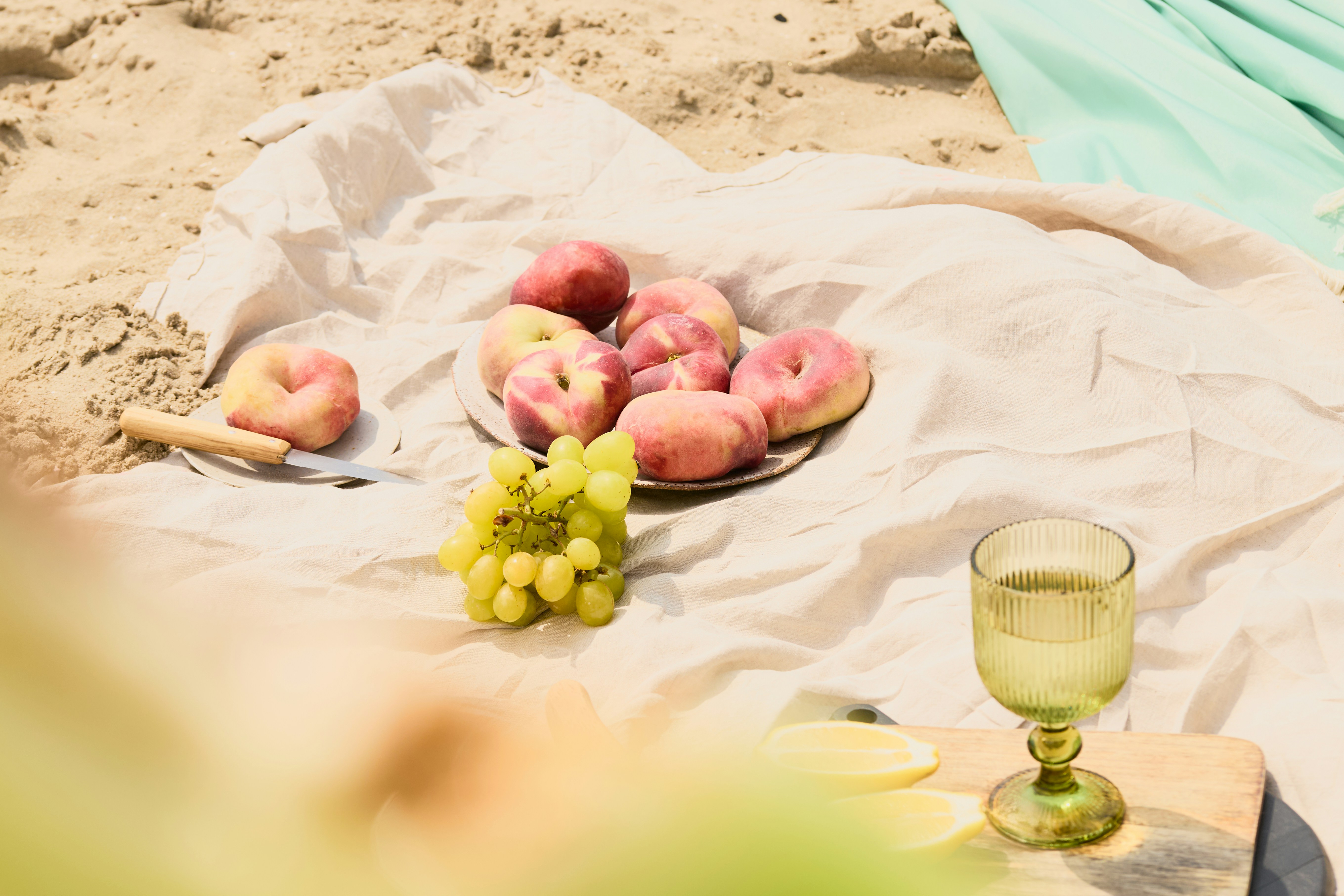 Picnic on the beach: fruits, glass, and a blanket.