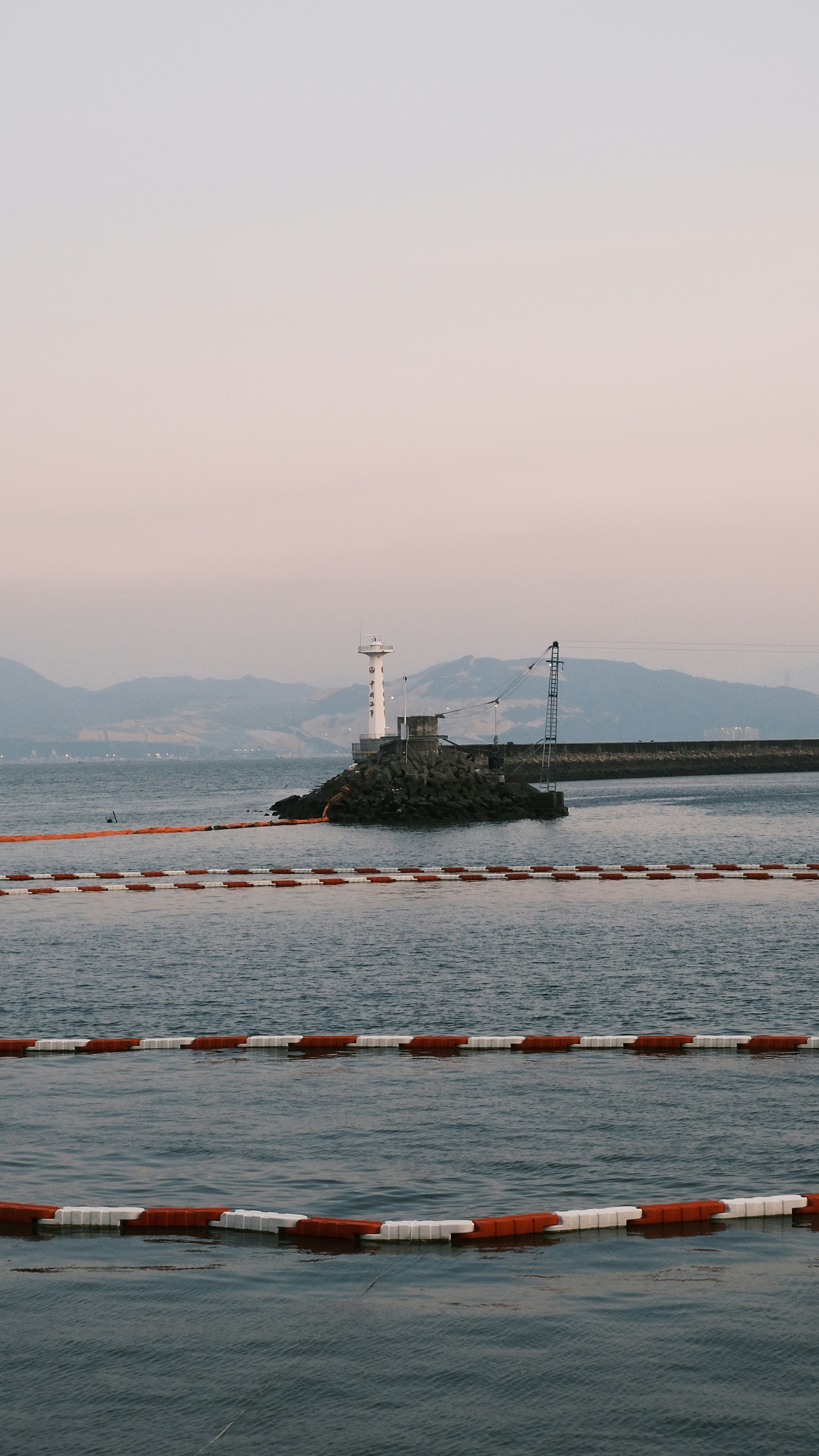 A lighthouse stands at the end of a breakwater.
