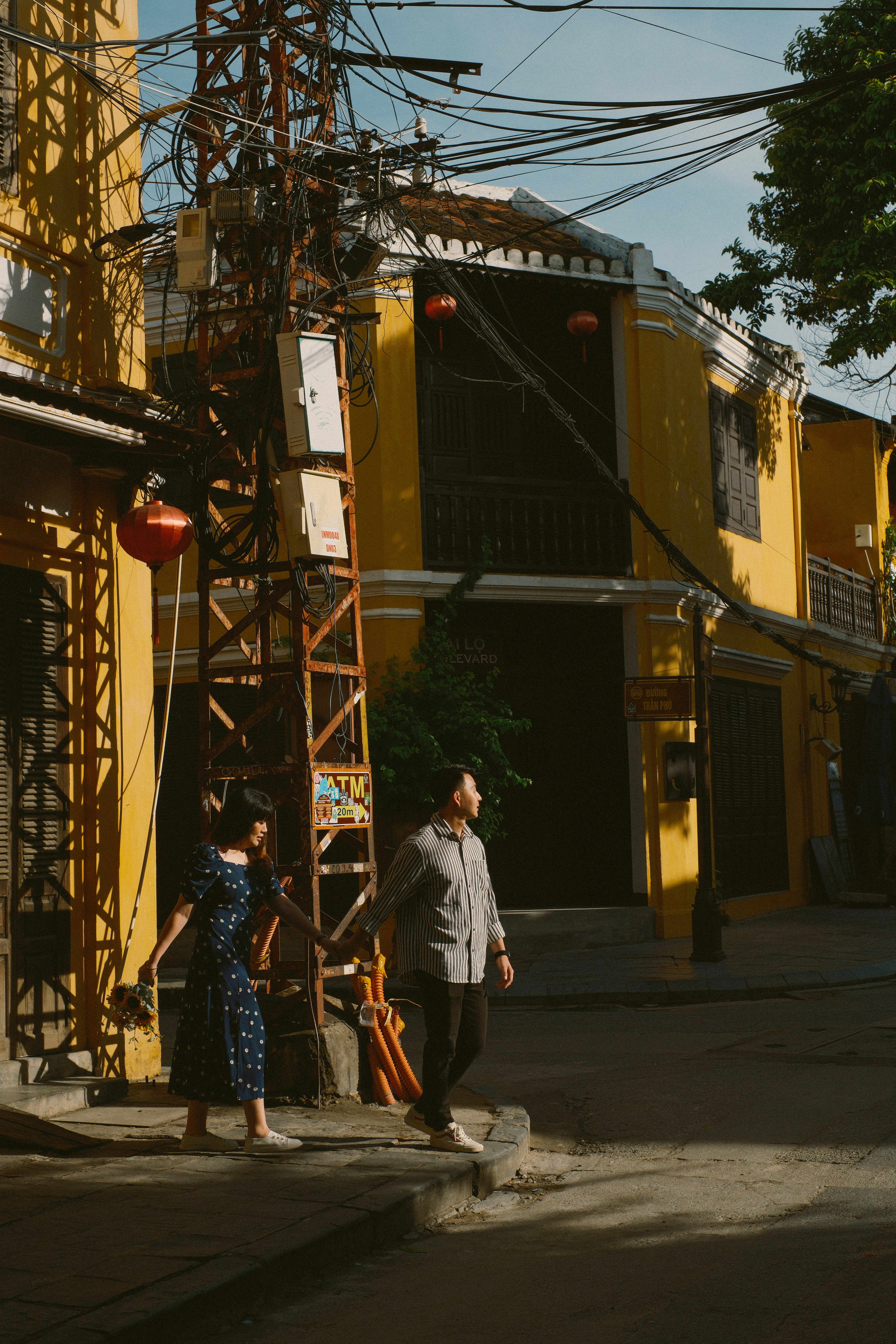 A couple walks down a sunny street.