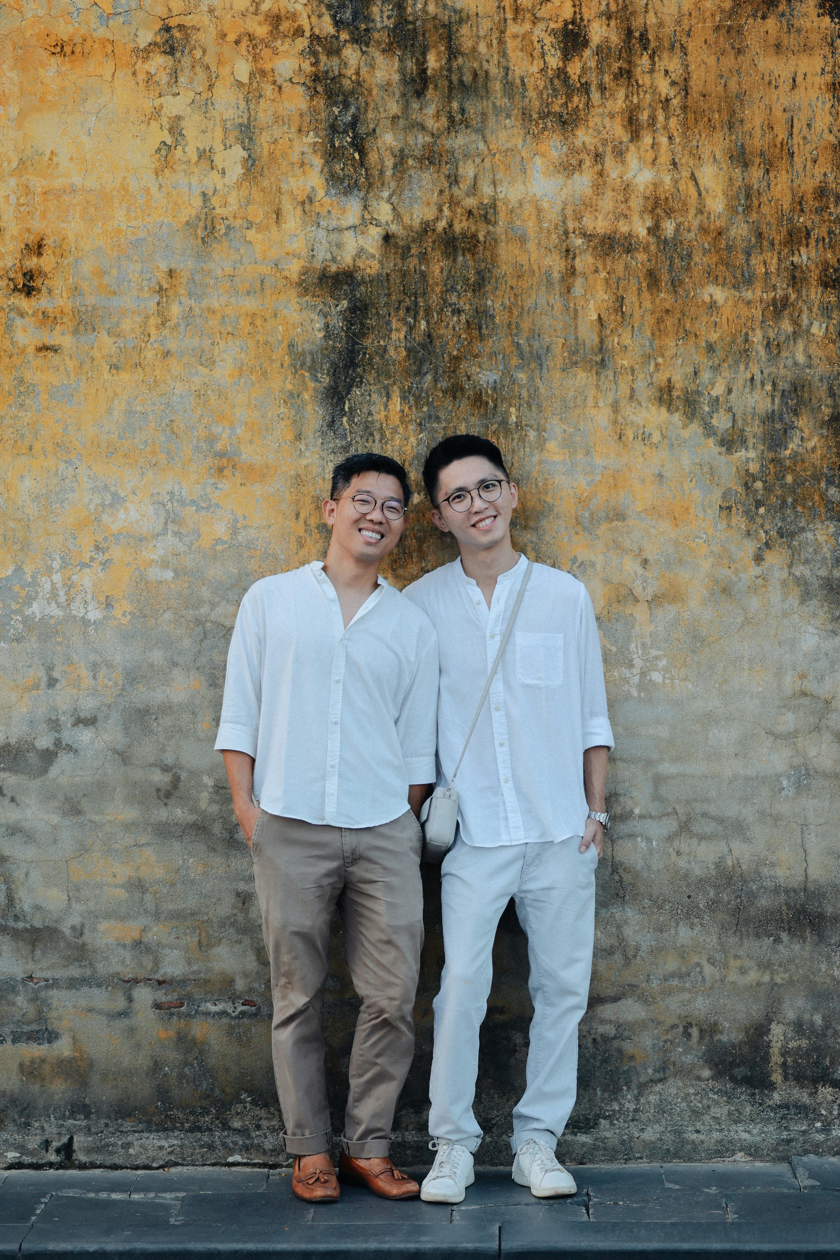 Two smiling men pose in front of a textured wall. photo – Free Portrait ...