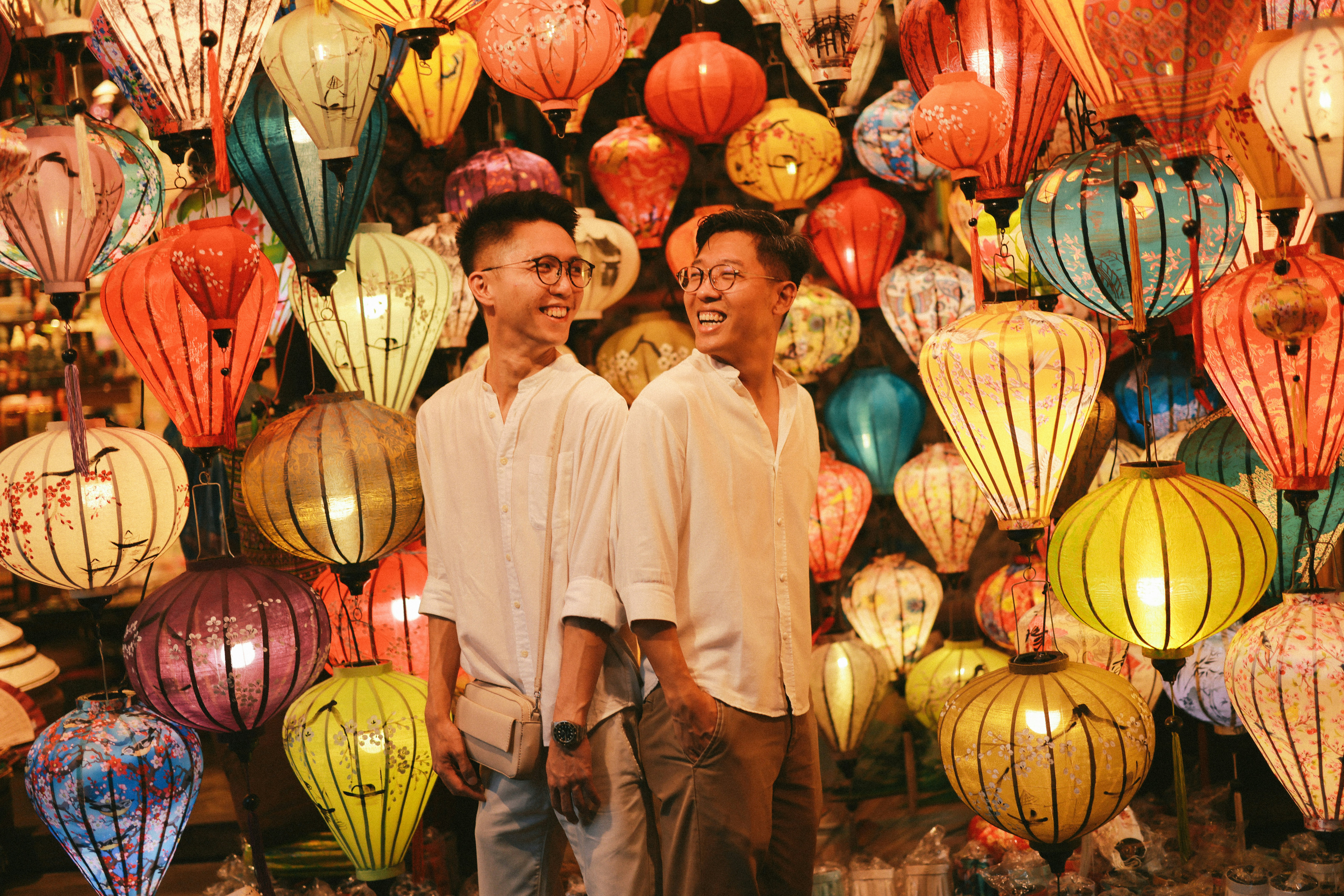 Two men pose amongst colorful lanterns.