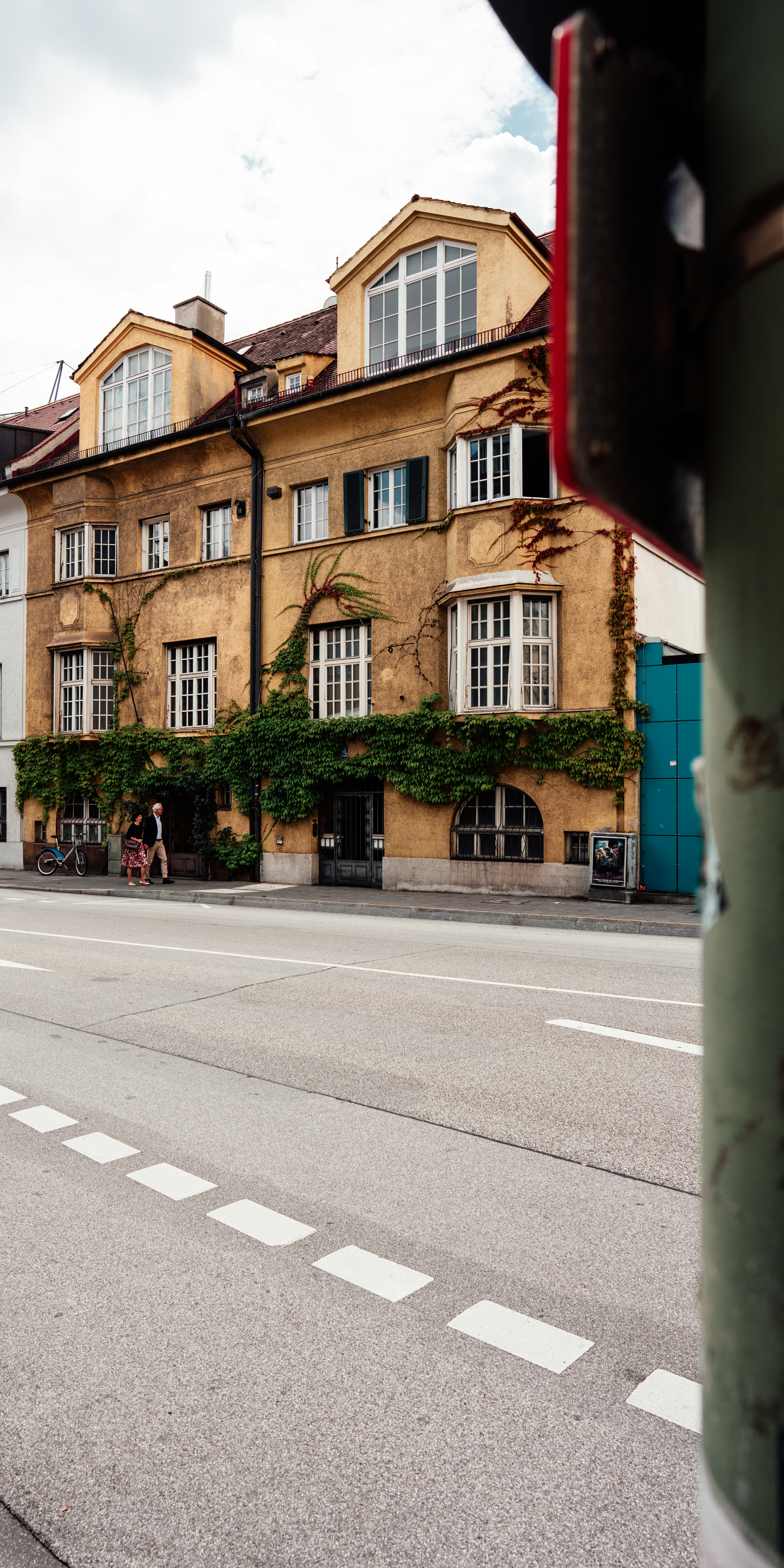 A yellow building with ivy stands beside a street.