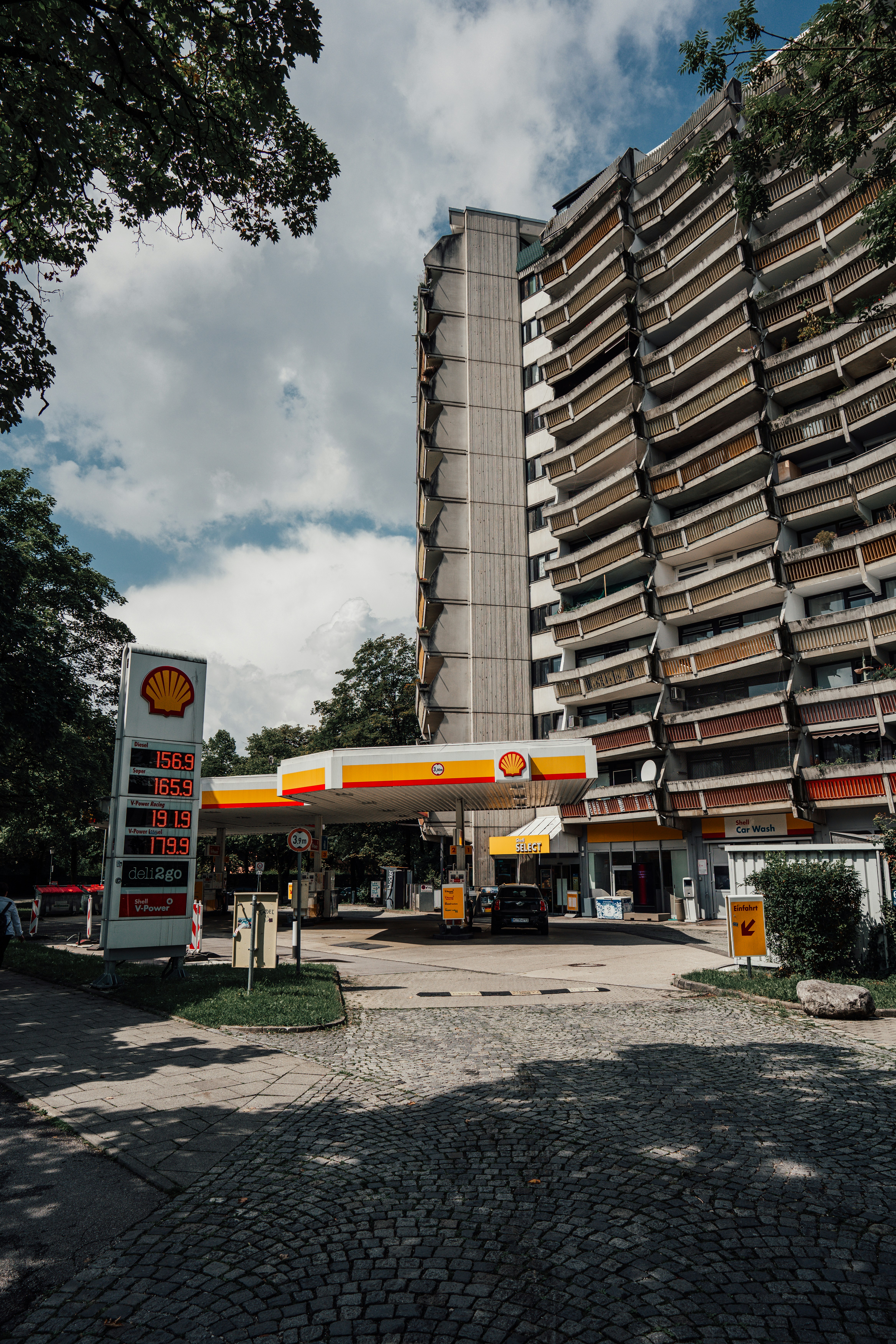 A shell gas station sits beside a tall apartment building.