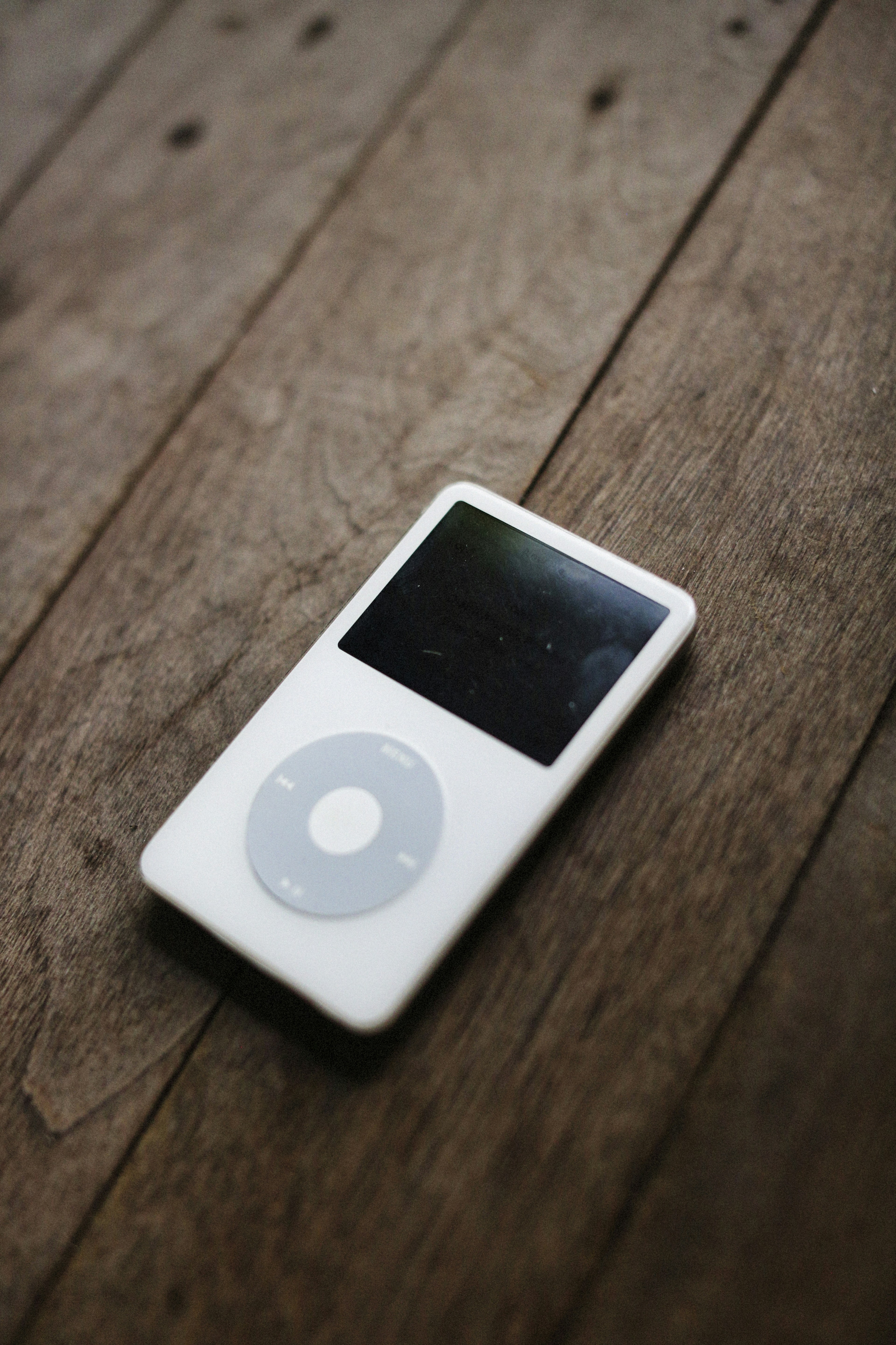 An old iPod sits on a wooden surface.