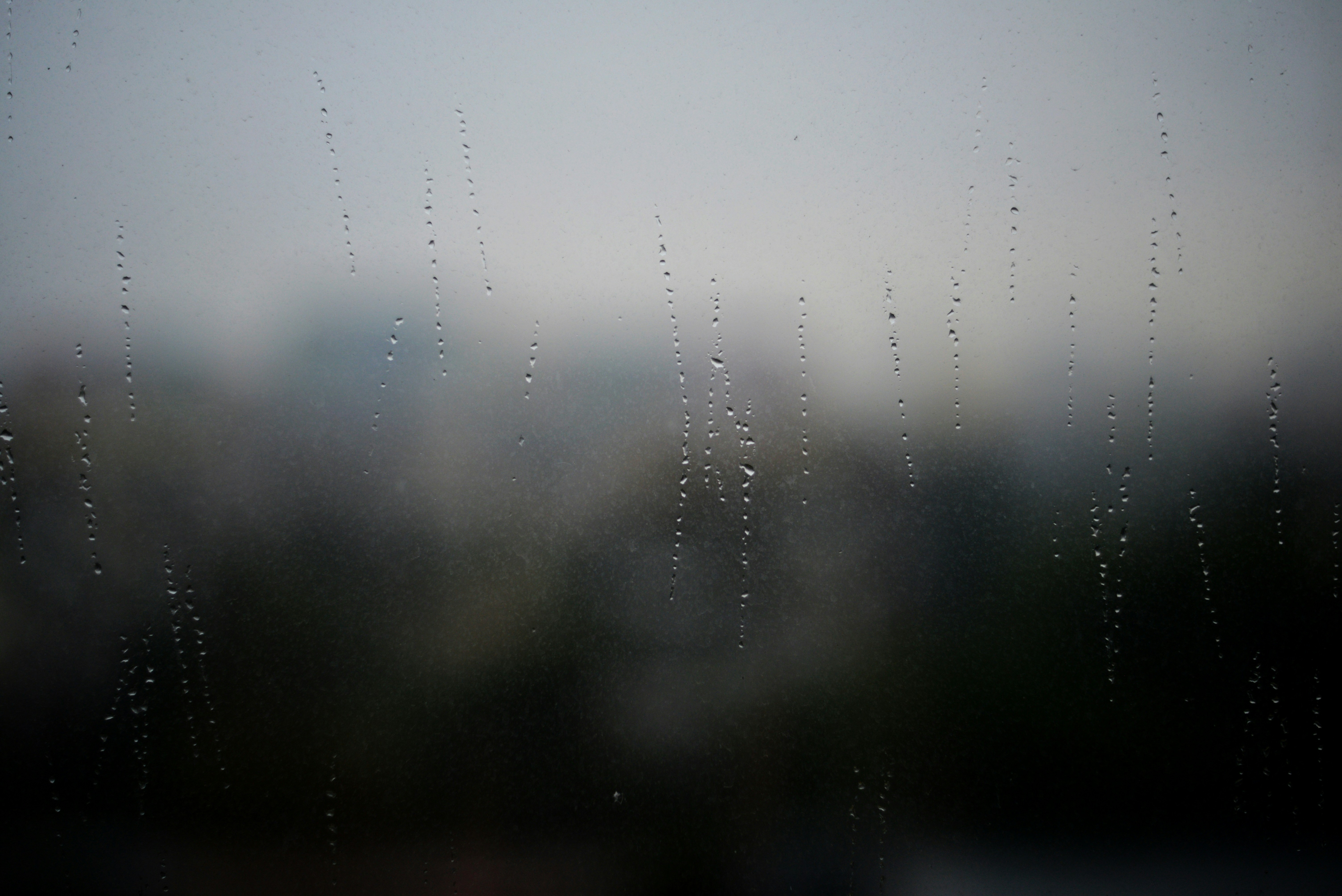 Raindrops trickle down a misty windowpane.