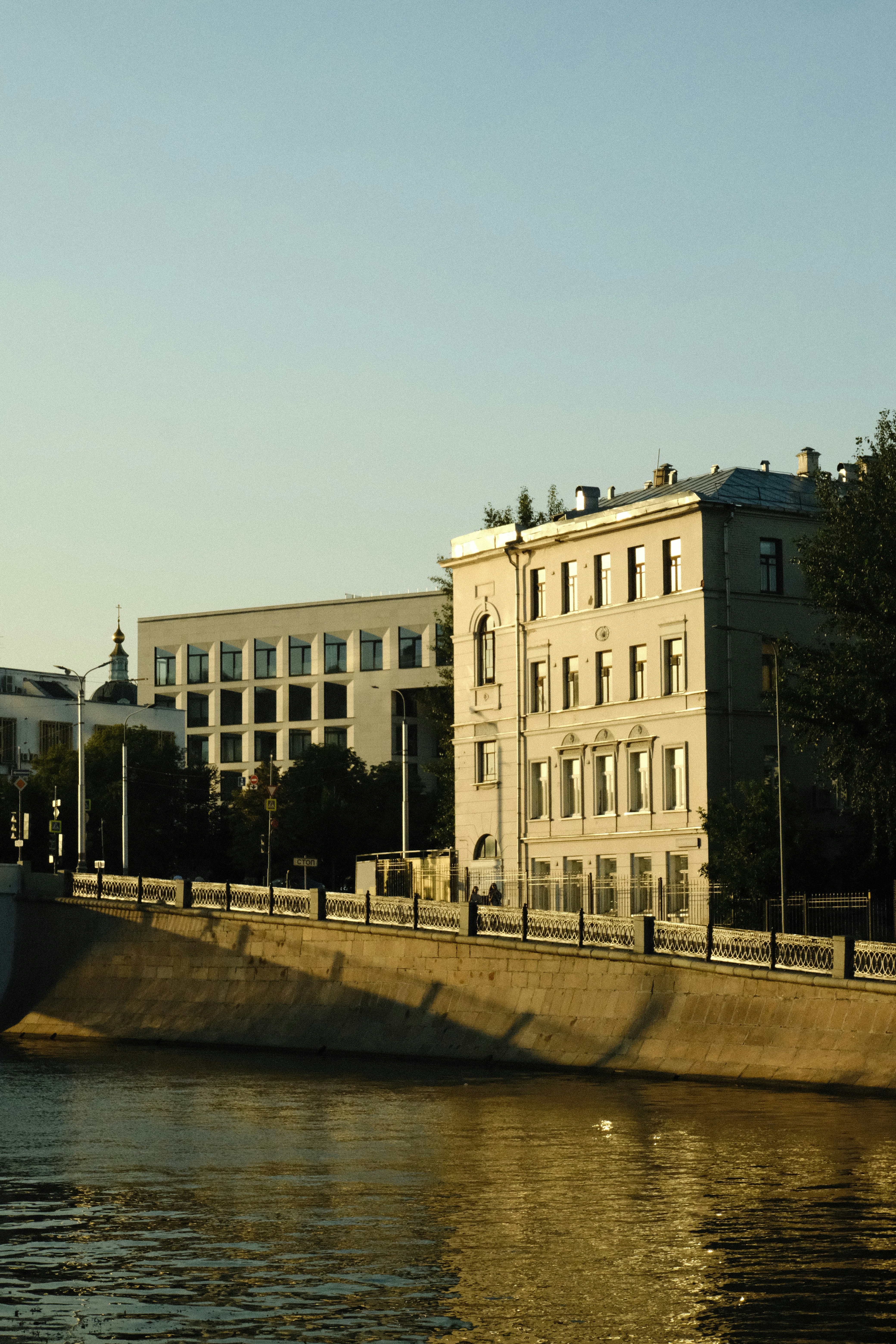 Buildings sit alongside a sunlit river.