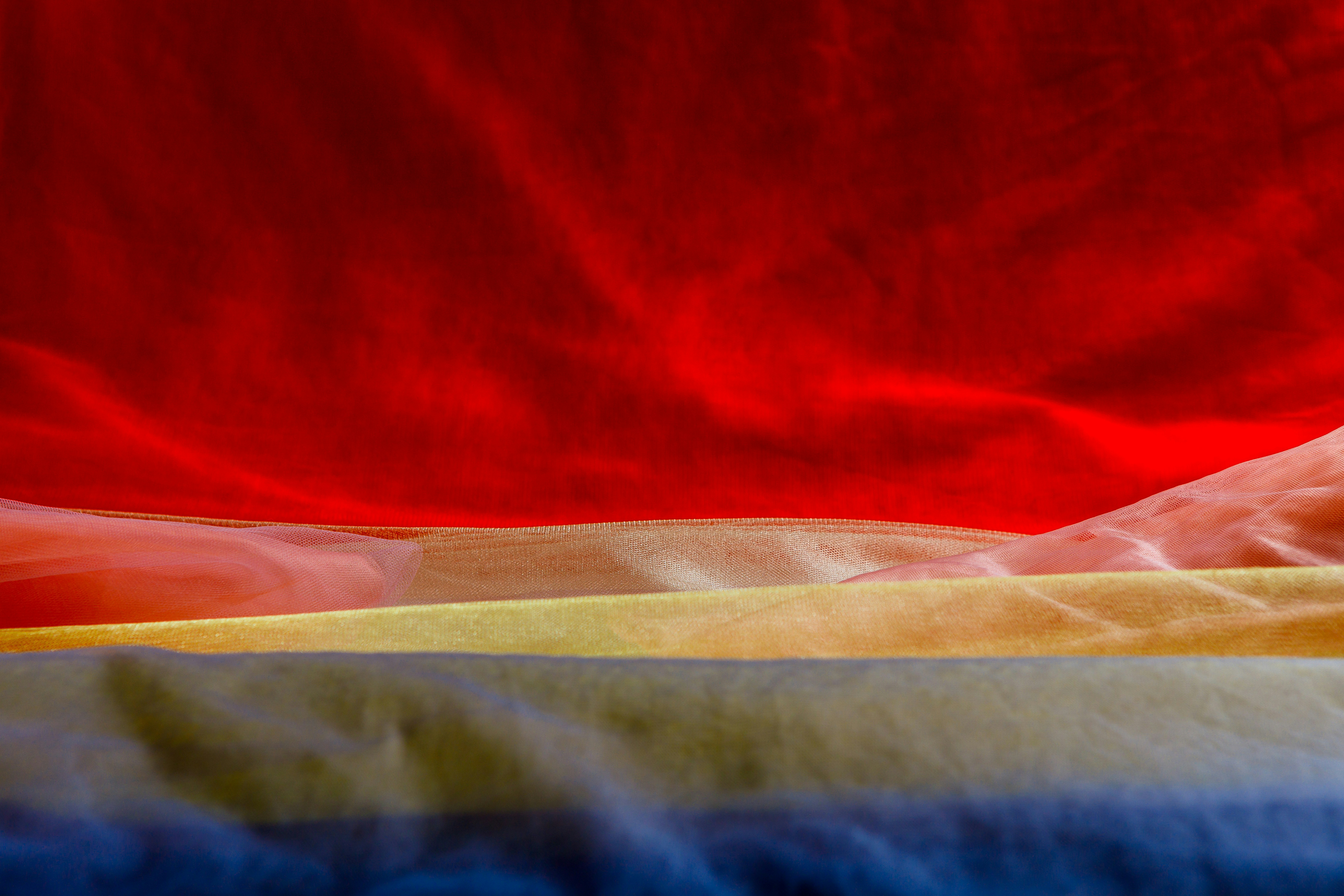 Vibrant layers of fabric in red, yellow, and blue create a harmonious blend, symbolizing diversity and inclusion.