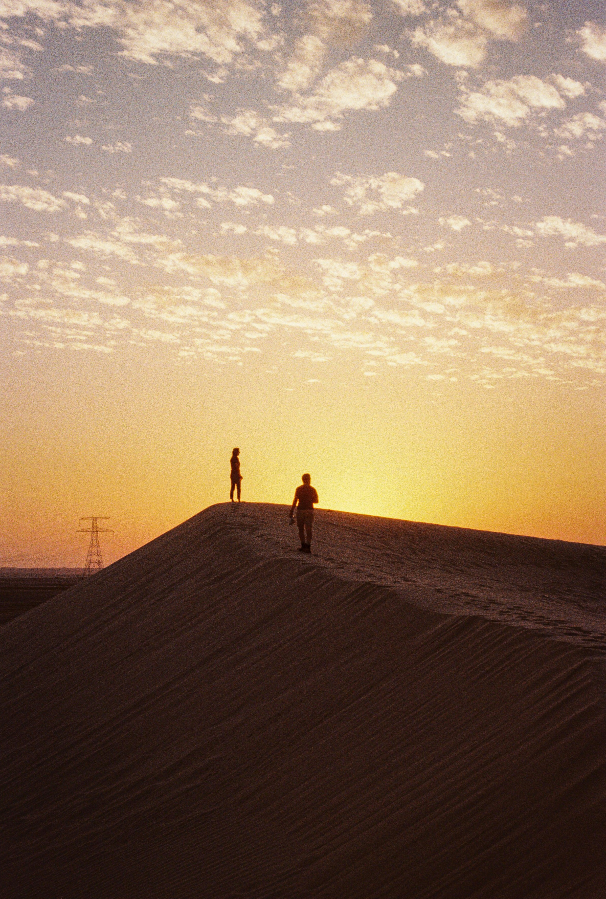 People watch the sunset from a desert dune.