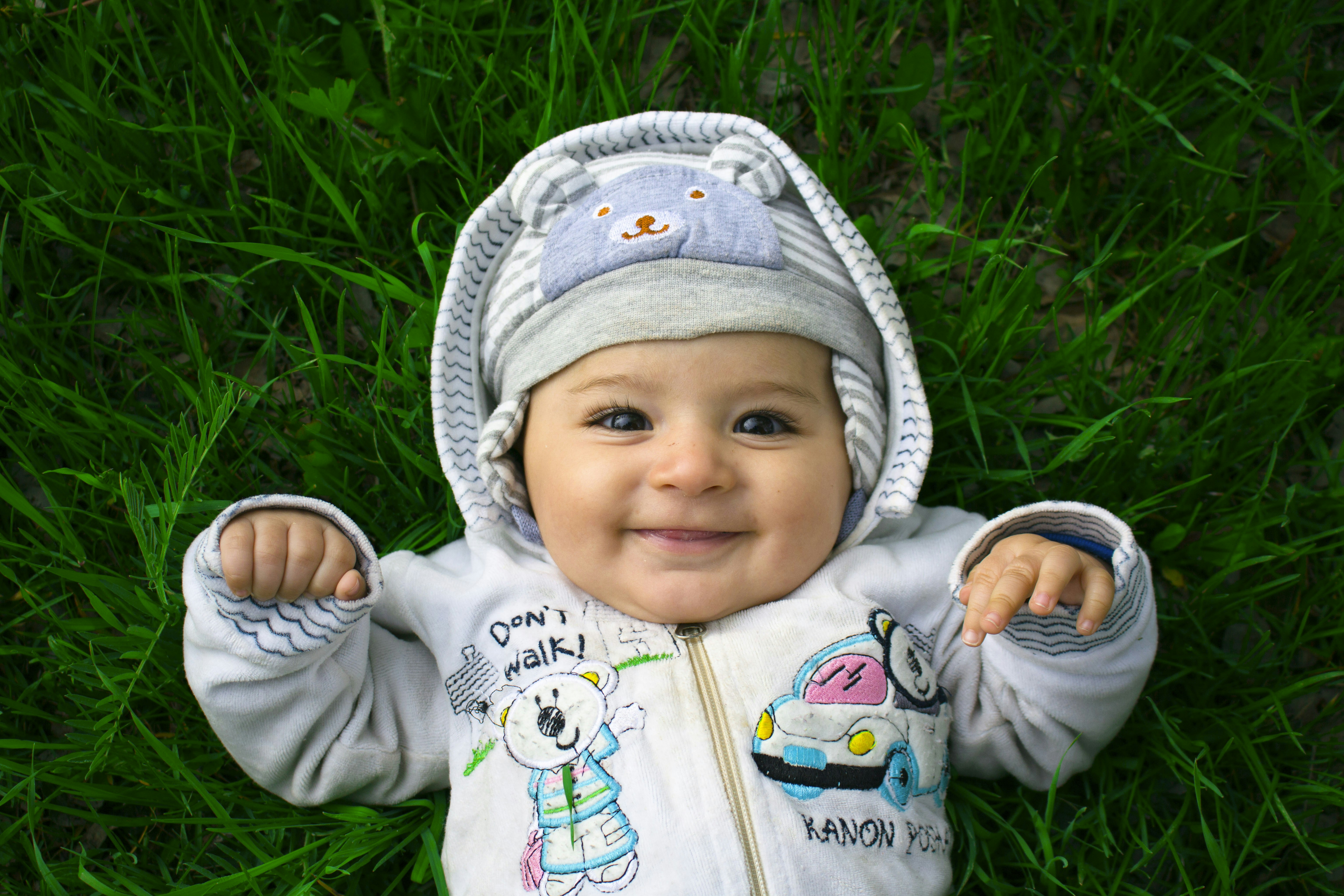Smiling baby lies on the grass, looking happy.