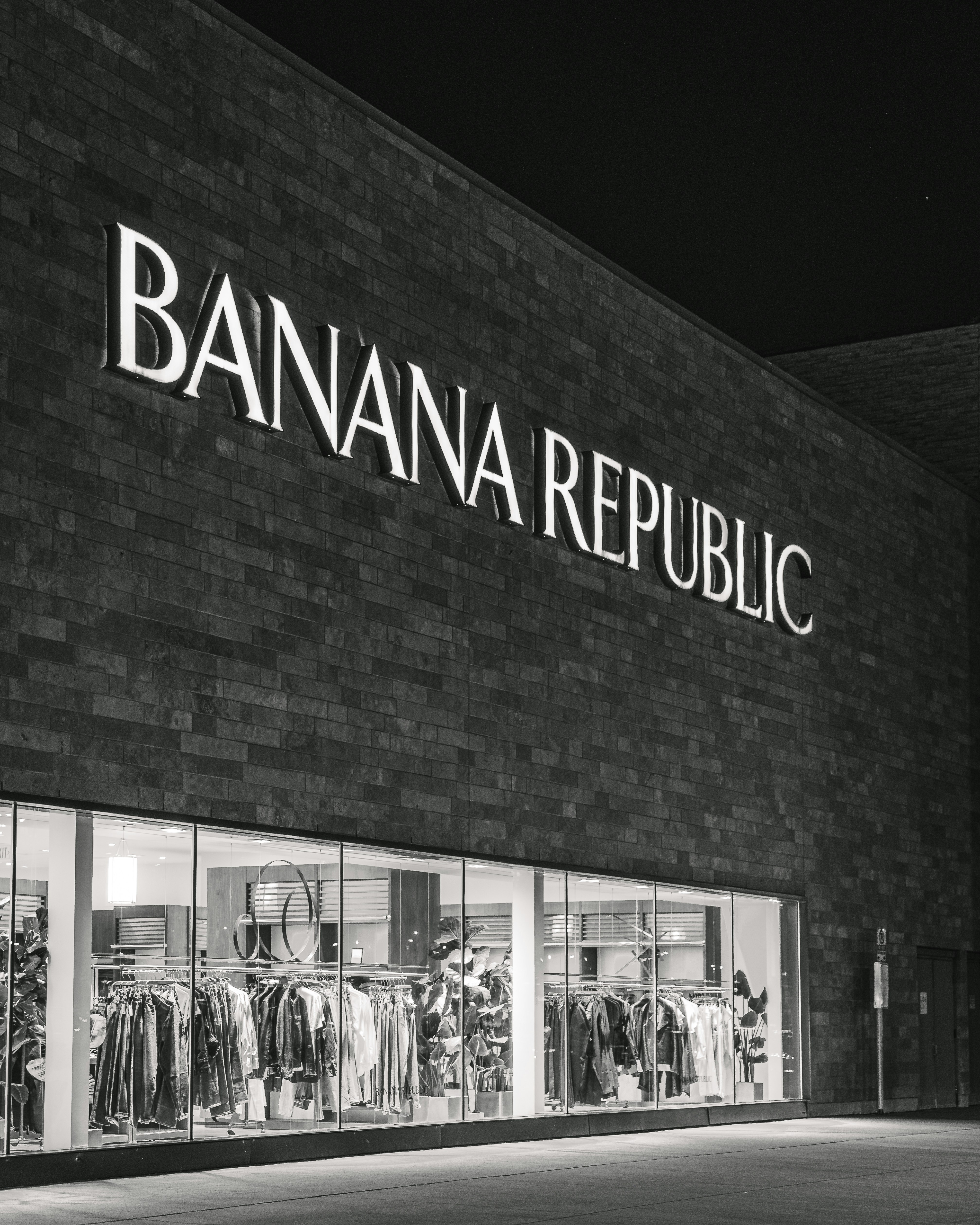 A clothing store at night in black and white. | Banana republic store sign illuminated at night.