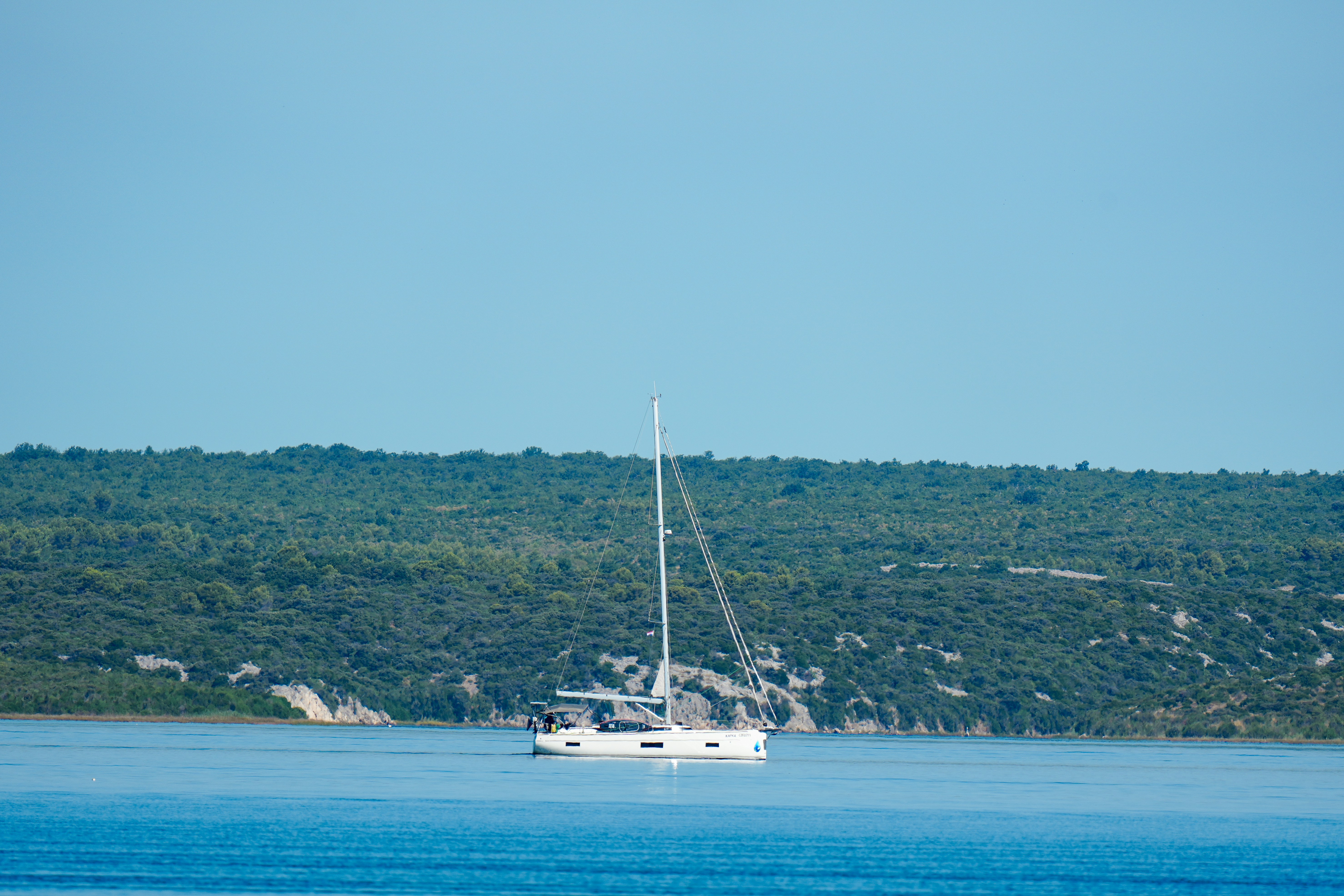 A sailboat peacefully sails on a calm sea.