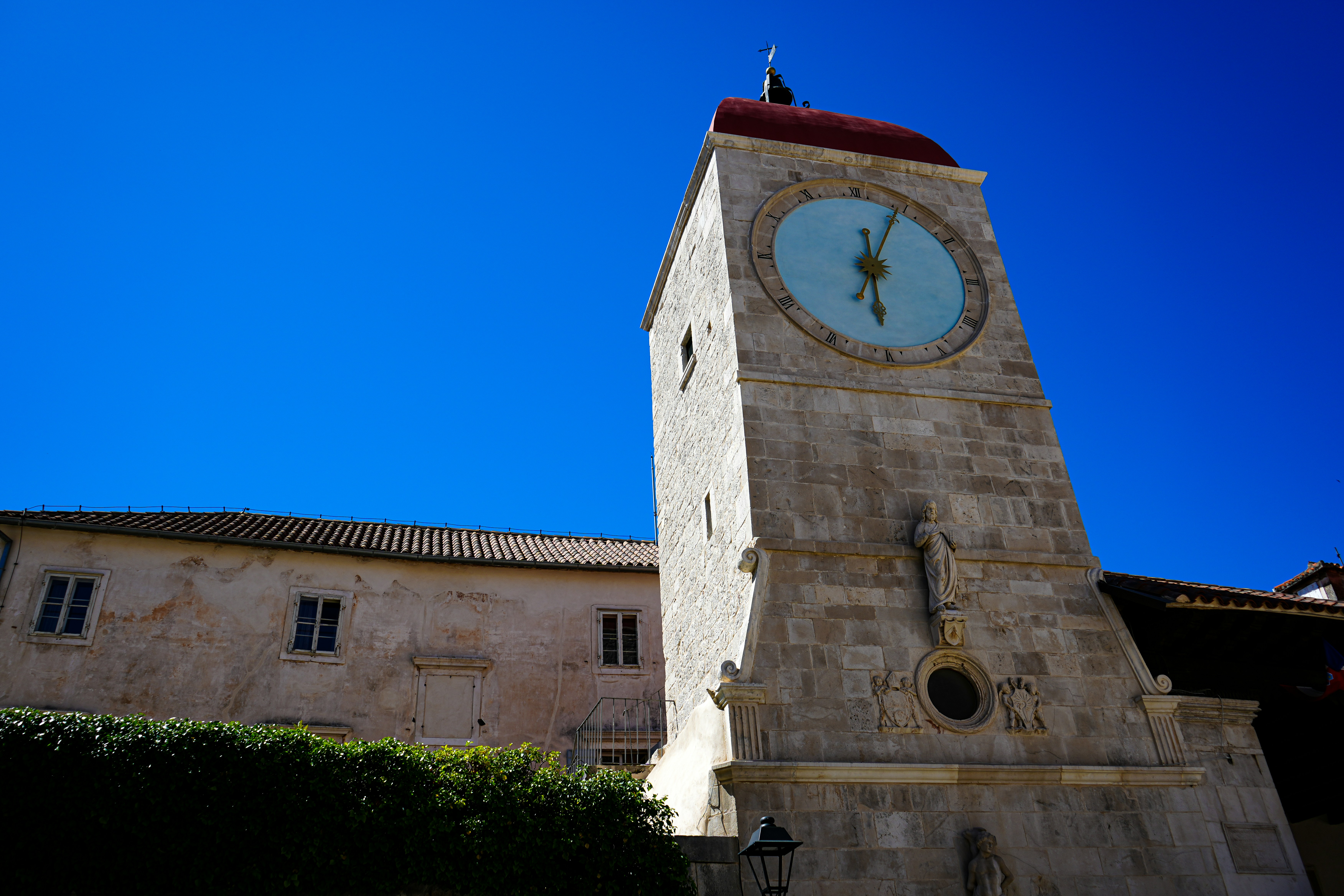 A stone clock tower underneath a clear blue sky.
