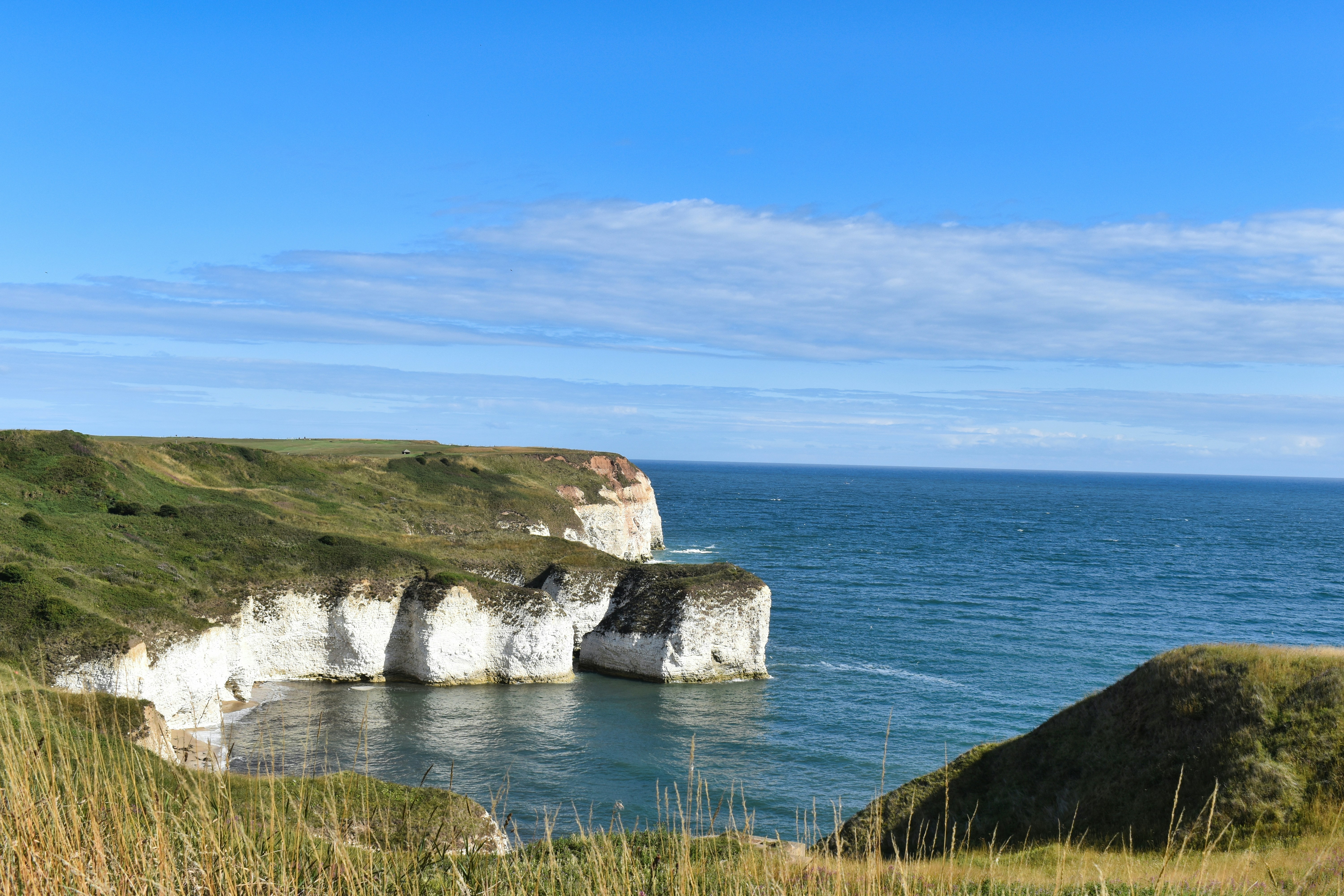 Majestic white cliffs meet the tranquil sea under a clear blue sky, showcasing the beauty of coastal nature.