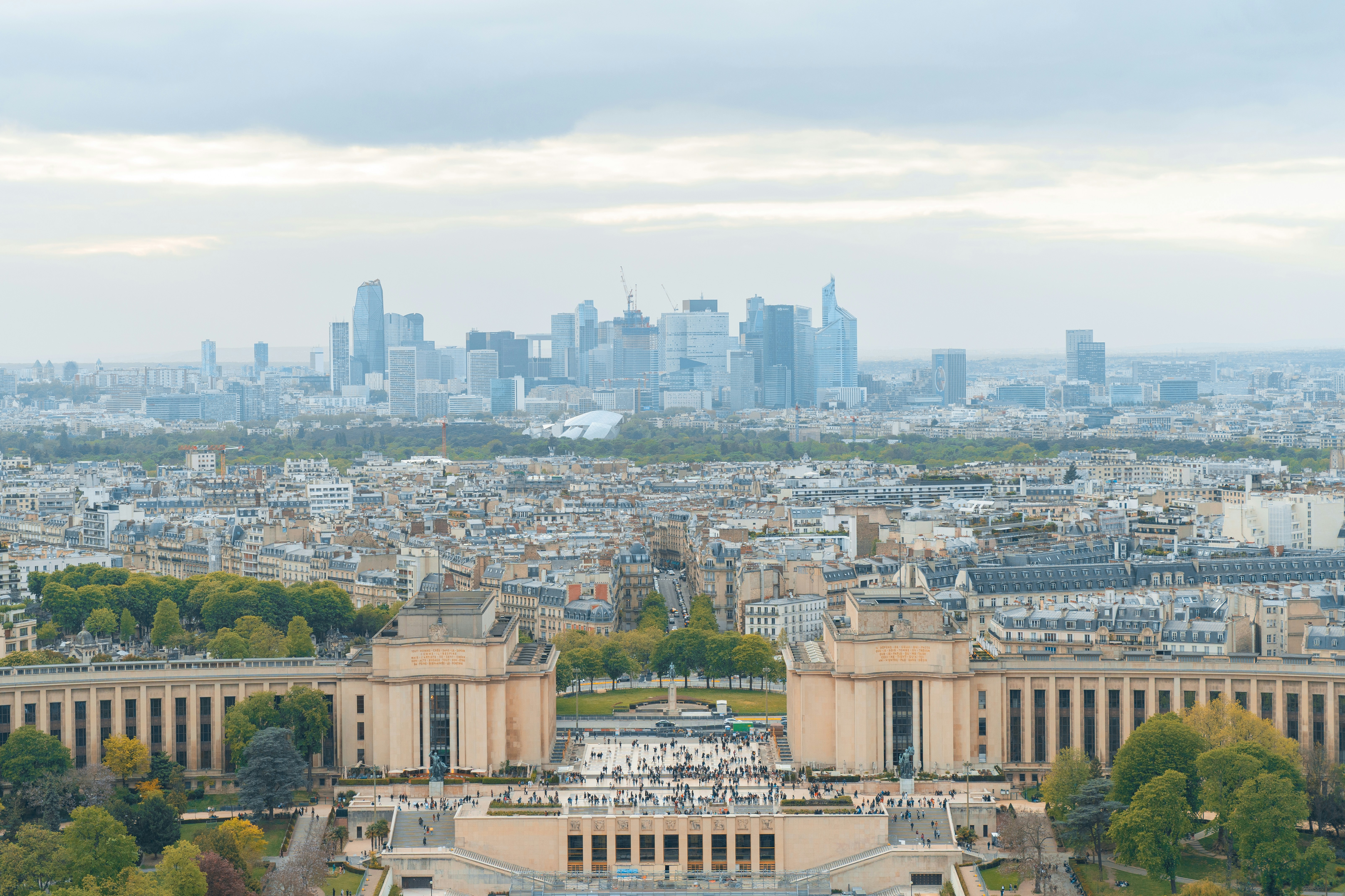 View from the Eiffel Tower towards Trocadéro and La Défense | Paris skyline with buildings under cloudy skies.