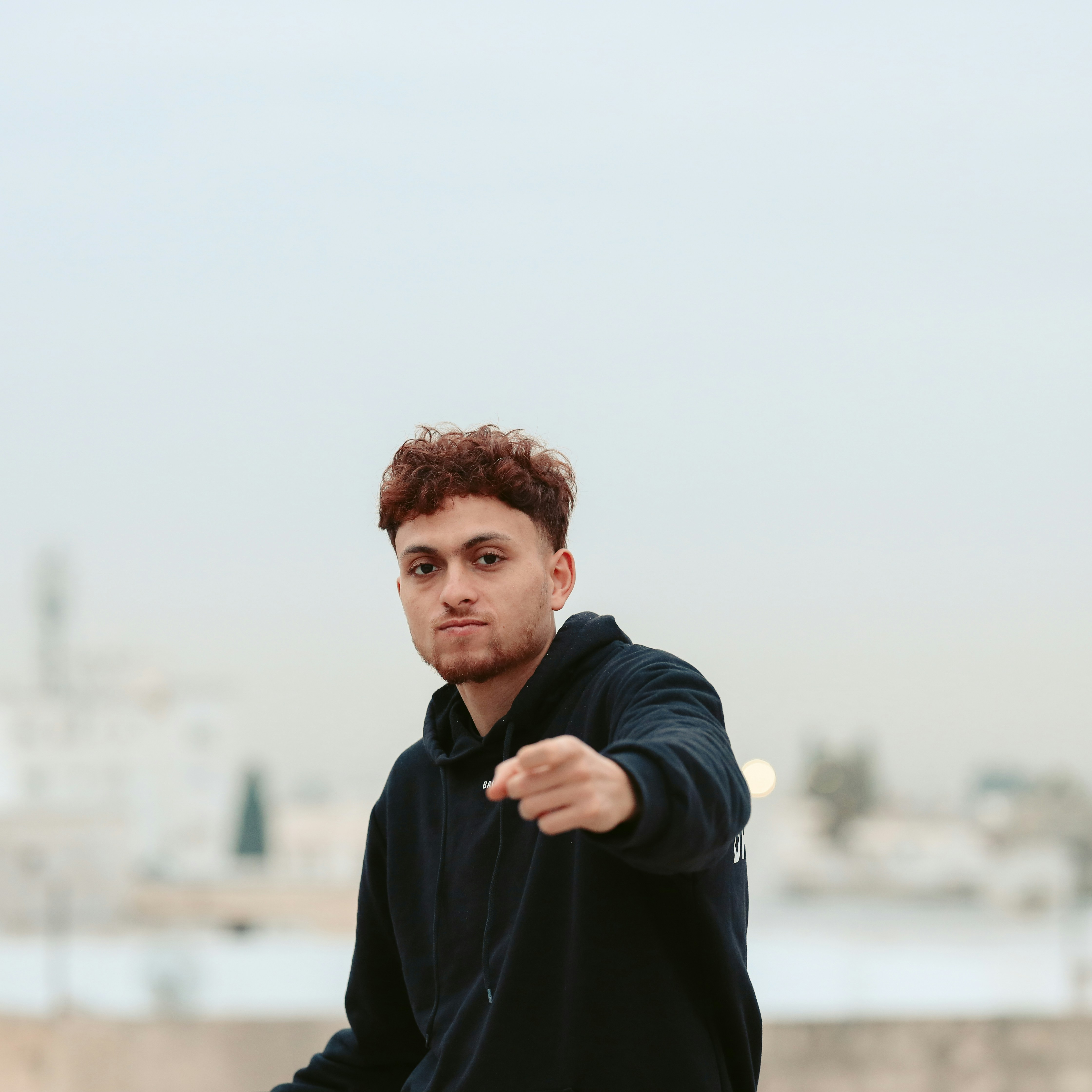 Young man points directly at the camera.