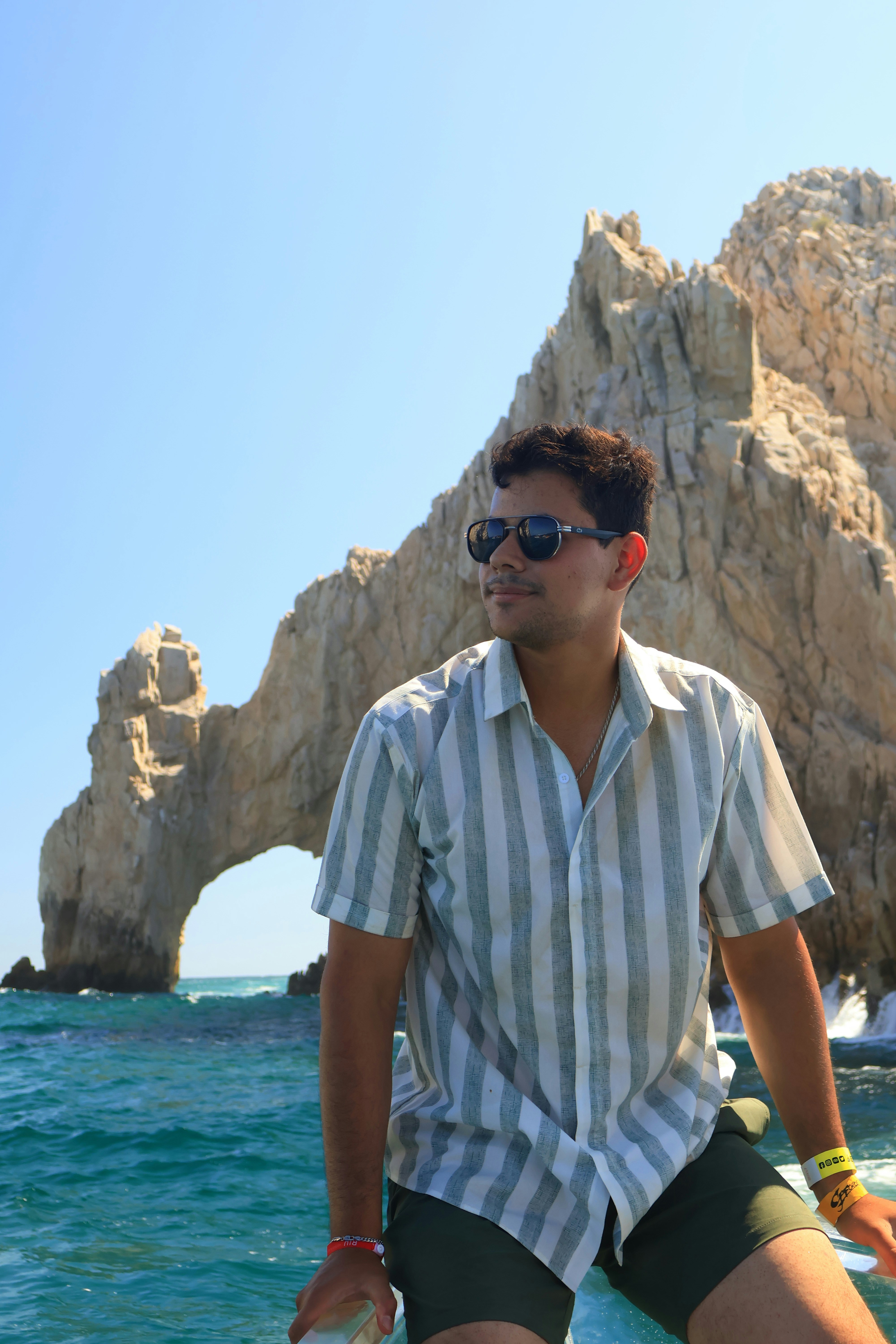 Me & My wife in Cabos | Man enjoys a boat ride near a rock formation.