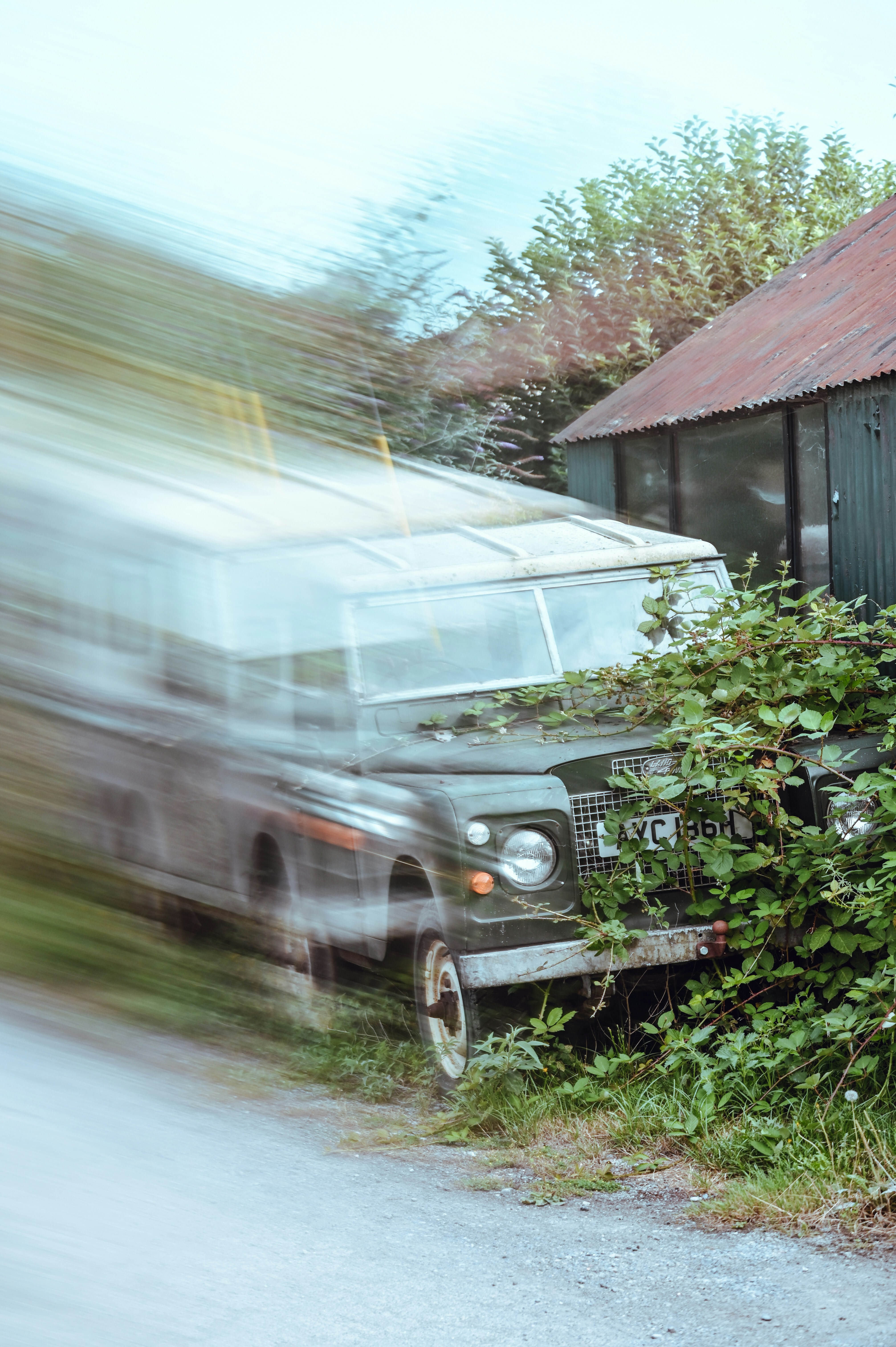 Reflect Lens Supernova Filter // 70-300 | A blurred land rover sits beside overgrown bushes.