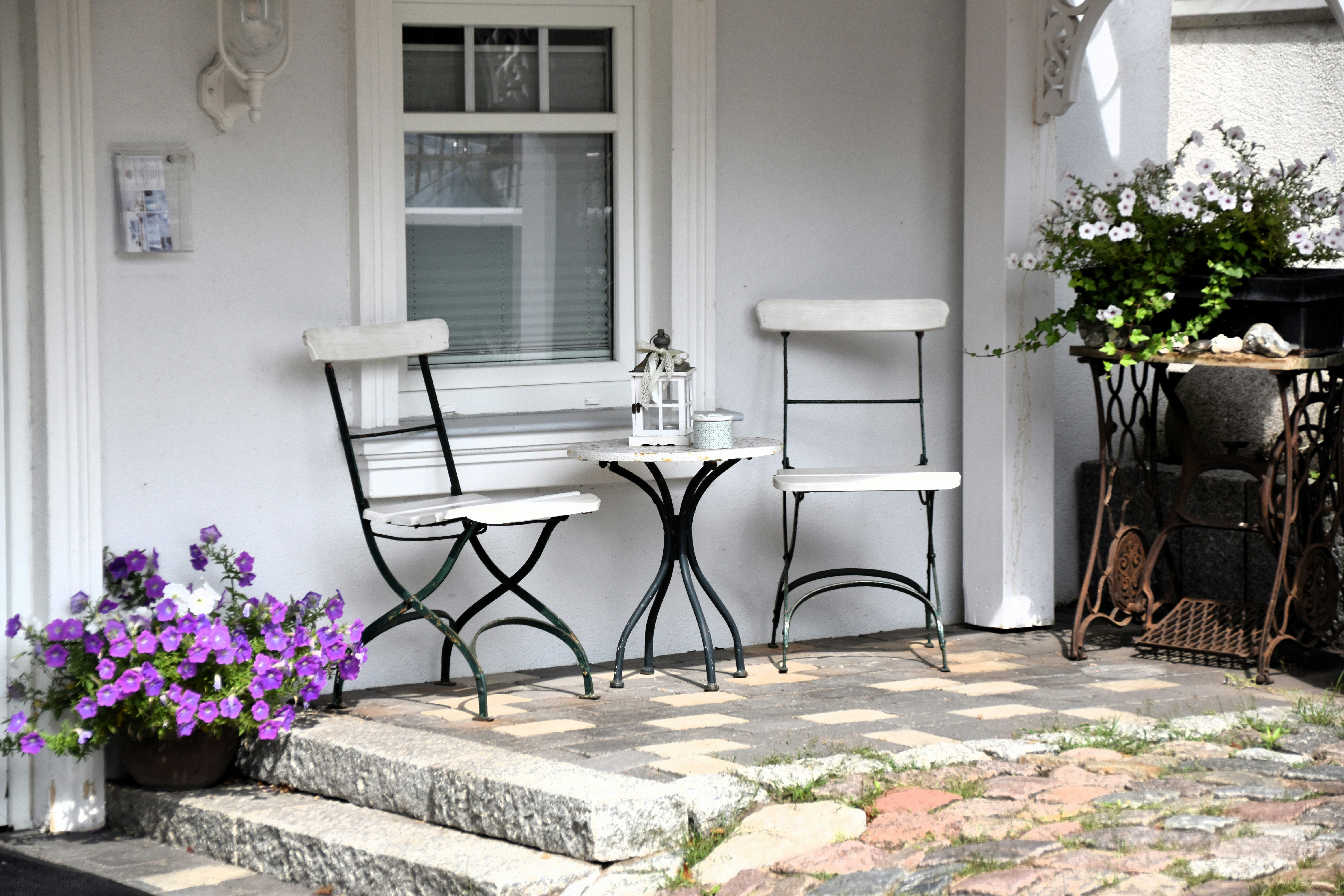 A cozy porch with chairs and flowers.