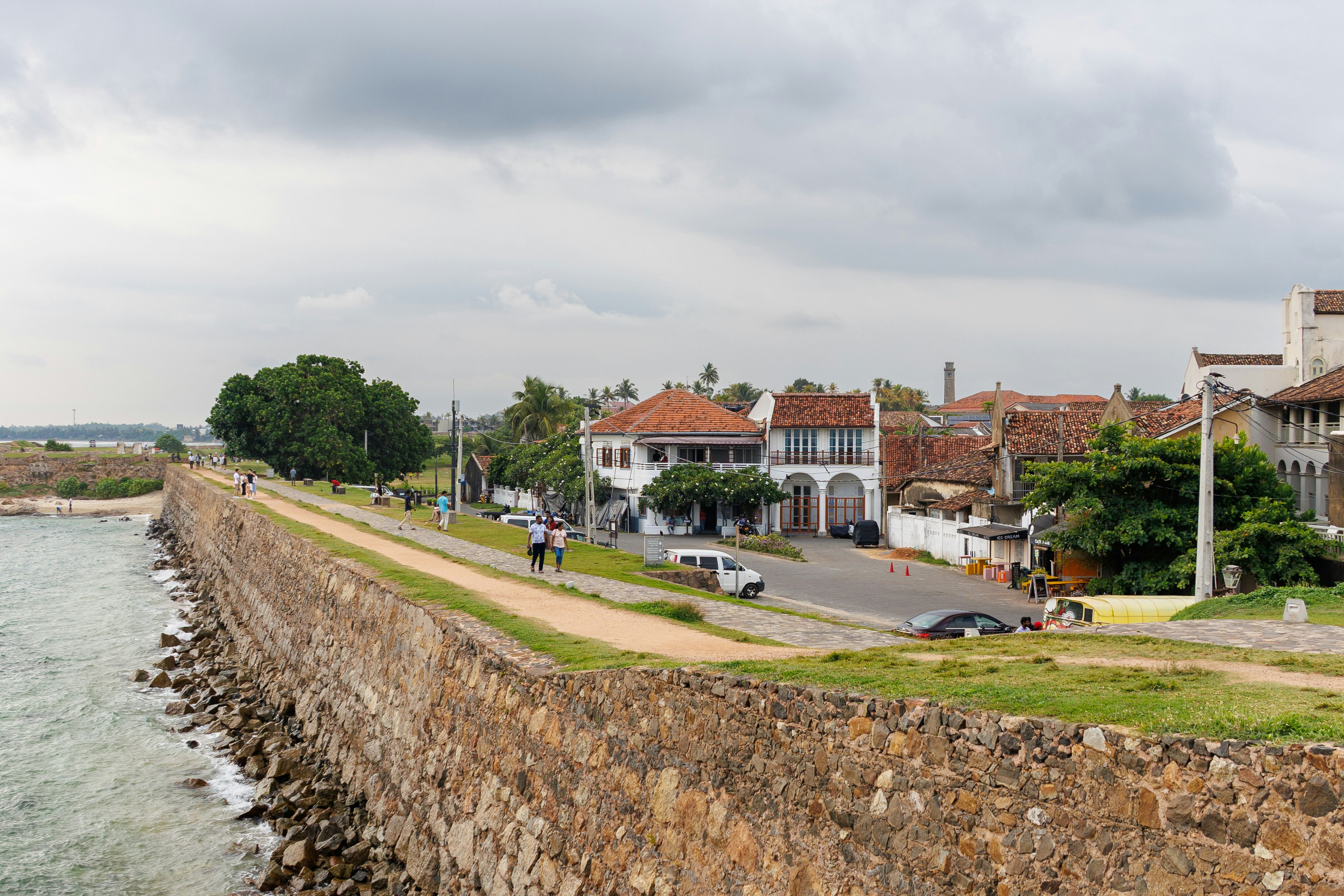 A stone wall overlooks a seaside town.