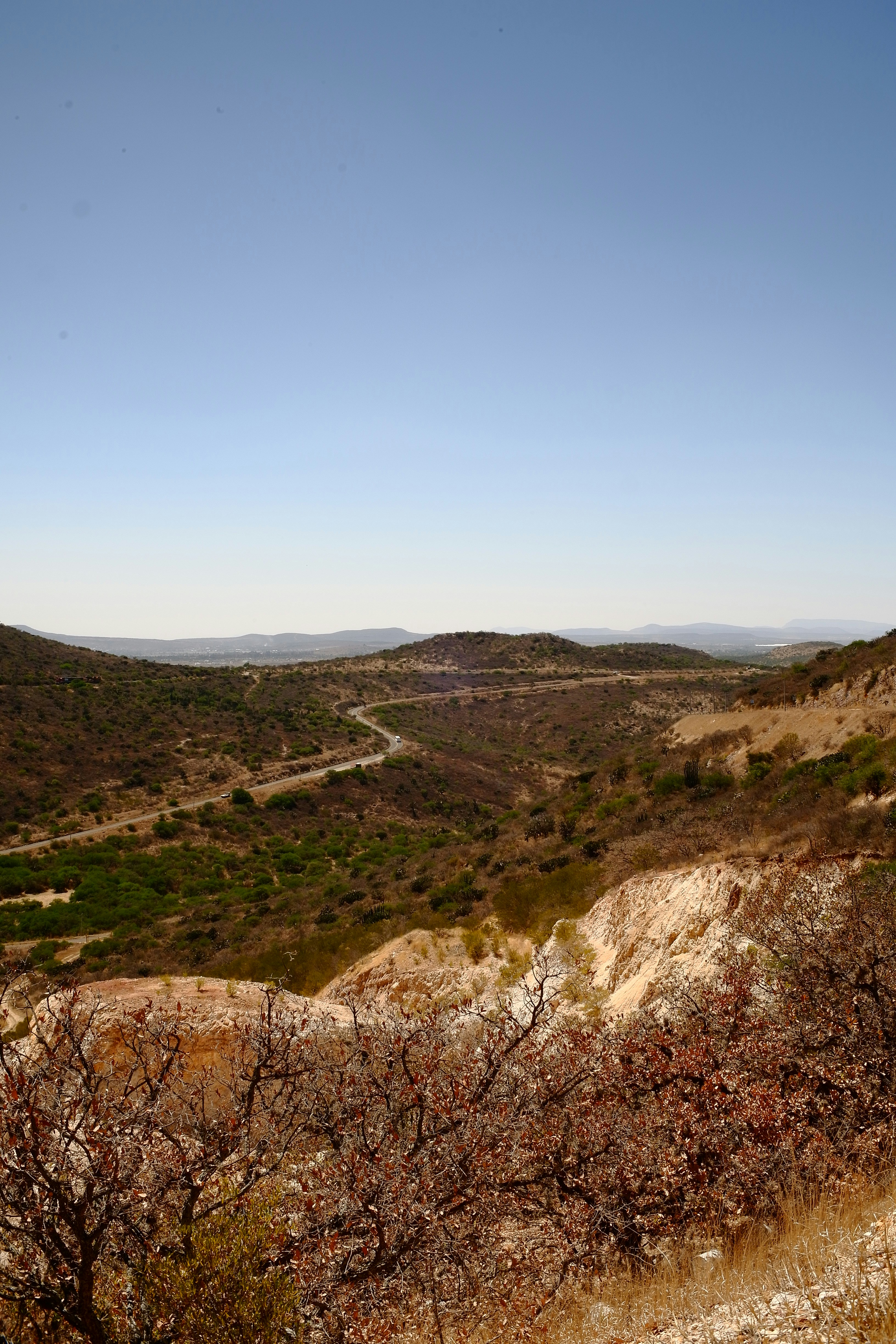 Rolling hills and winding road under a clear sky.