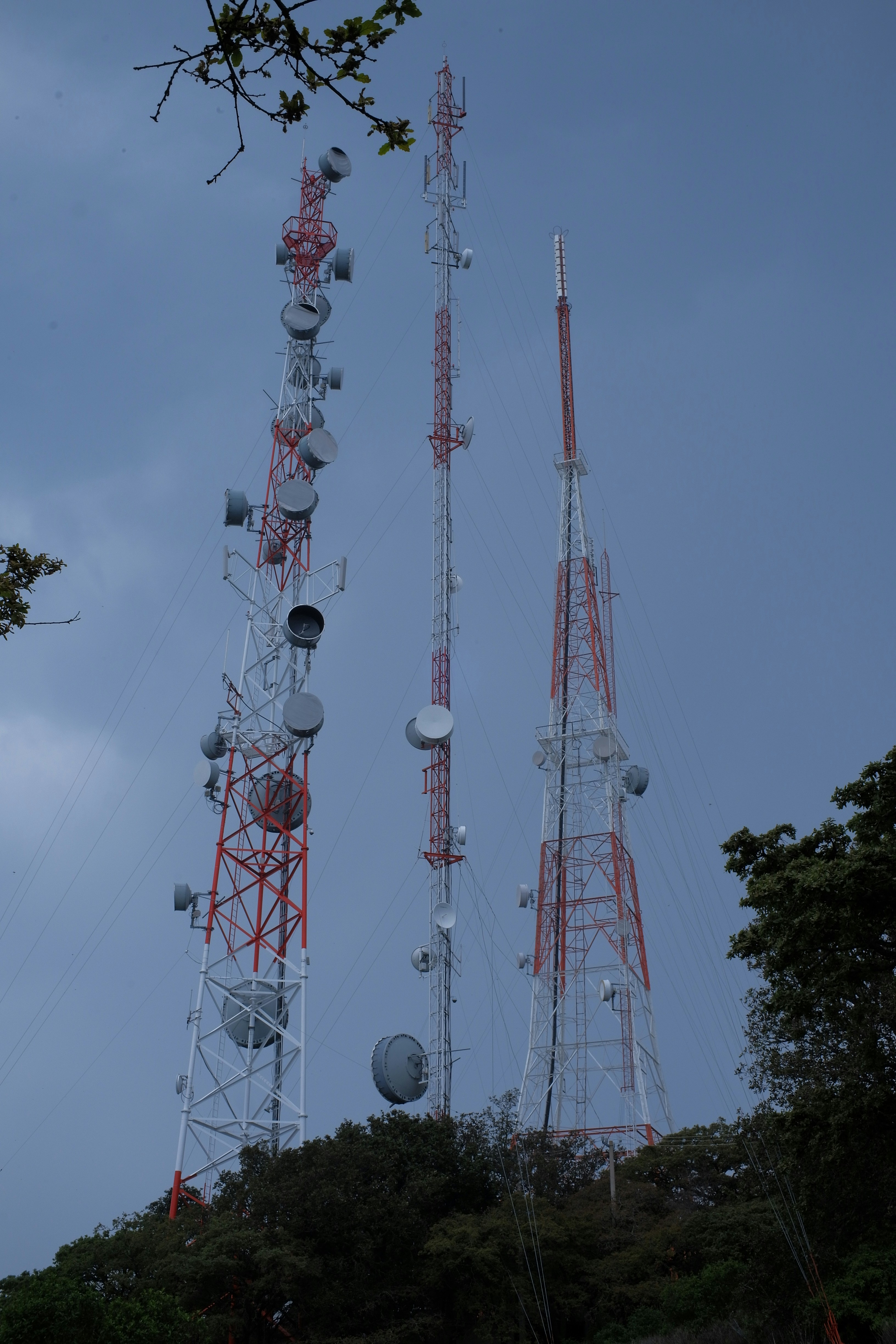 Communication towers stand tall against a cloudy sky.