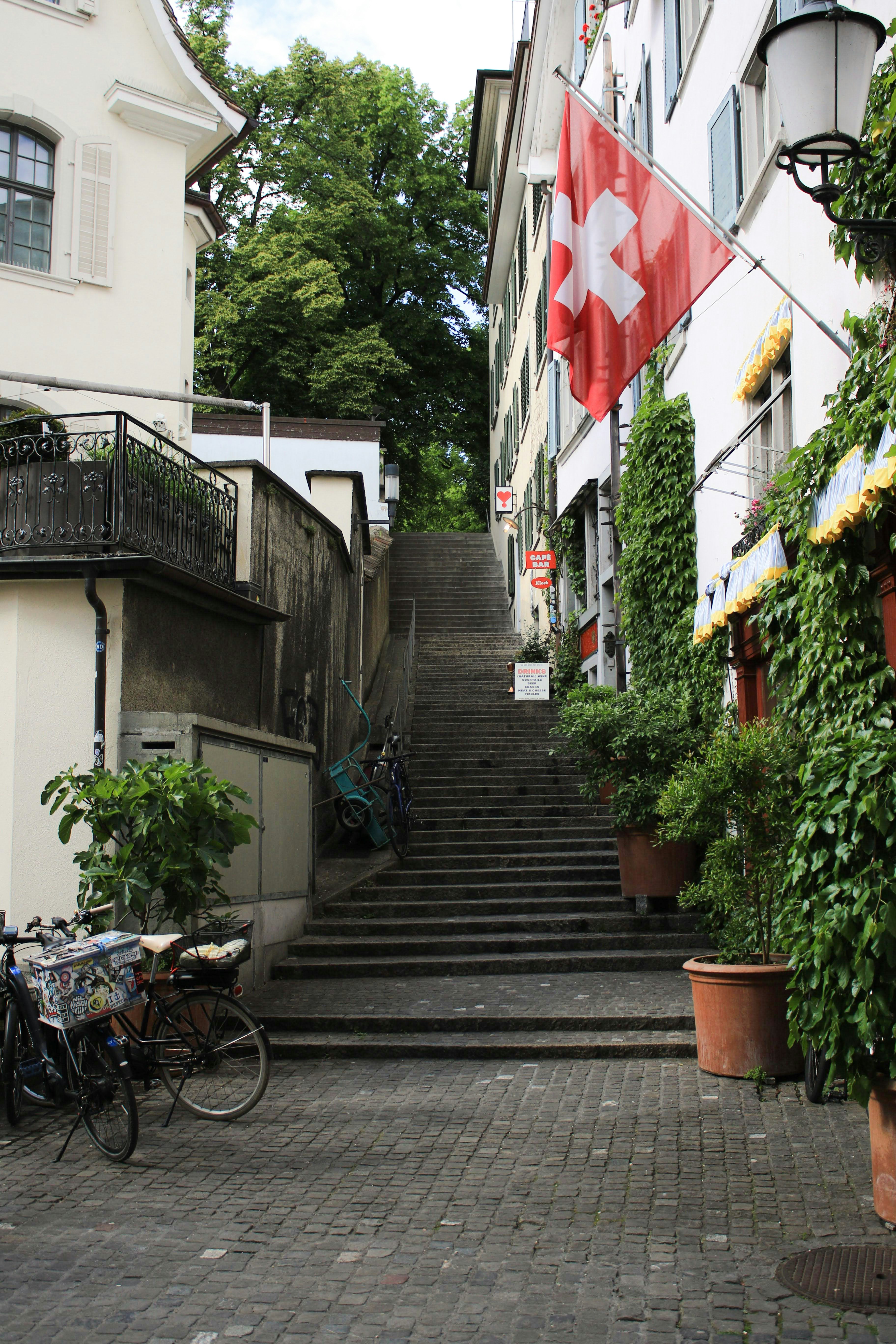 Swiss flag waves above stone steps in a town.
