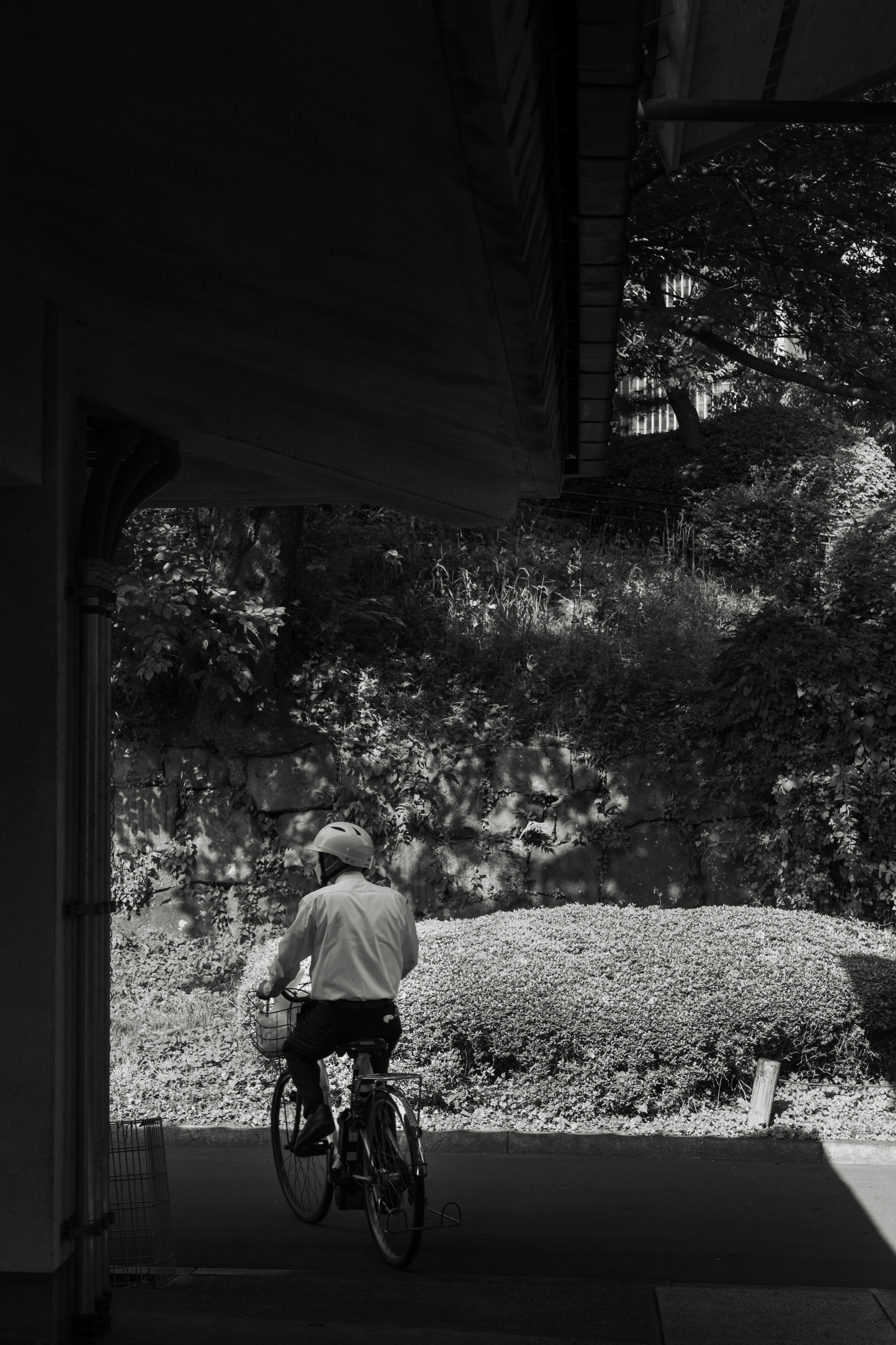 A person cycles out from under a shaded area.