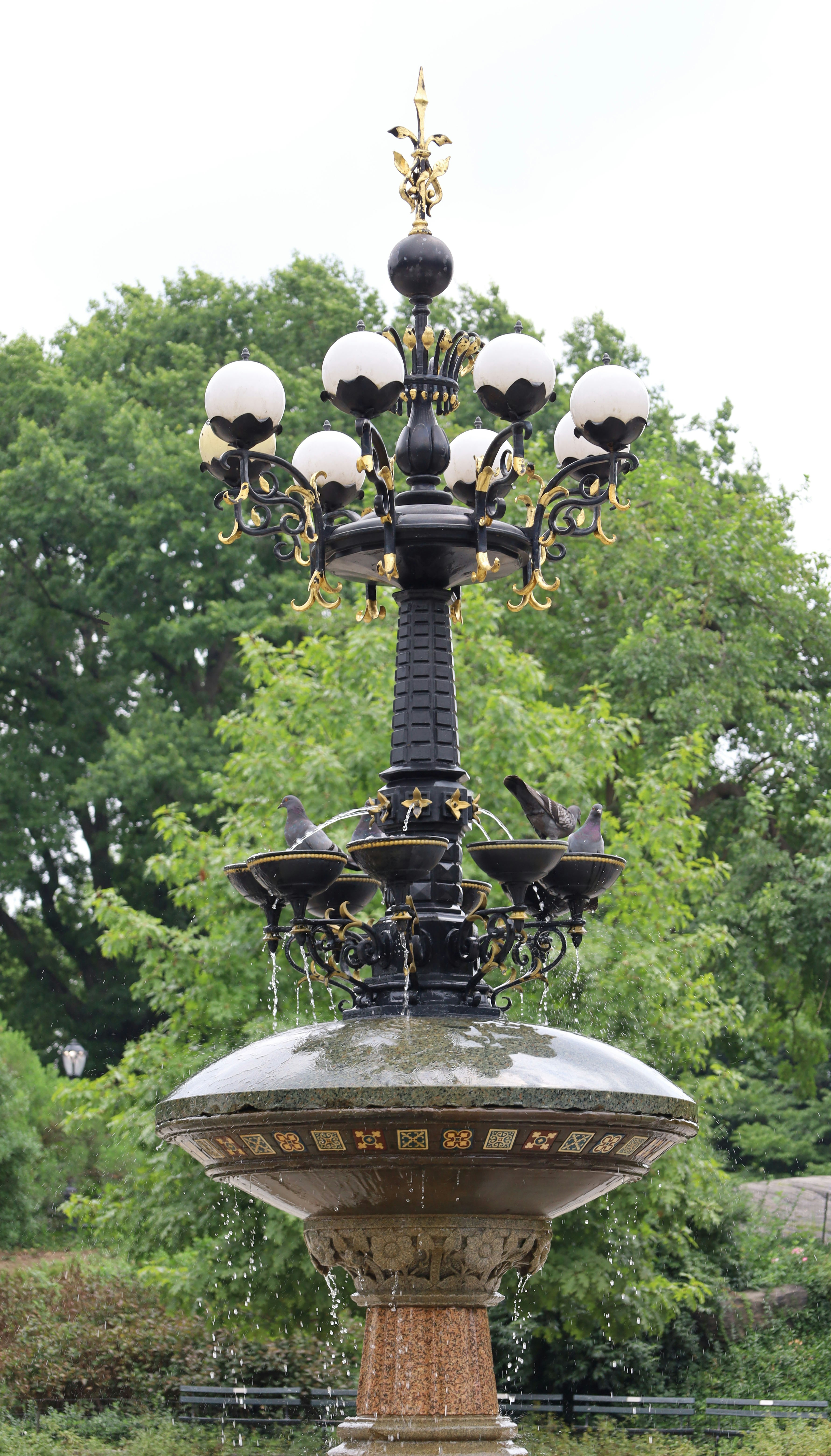 An ornate fountain with pigeons and lights.