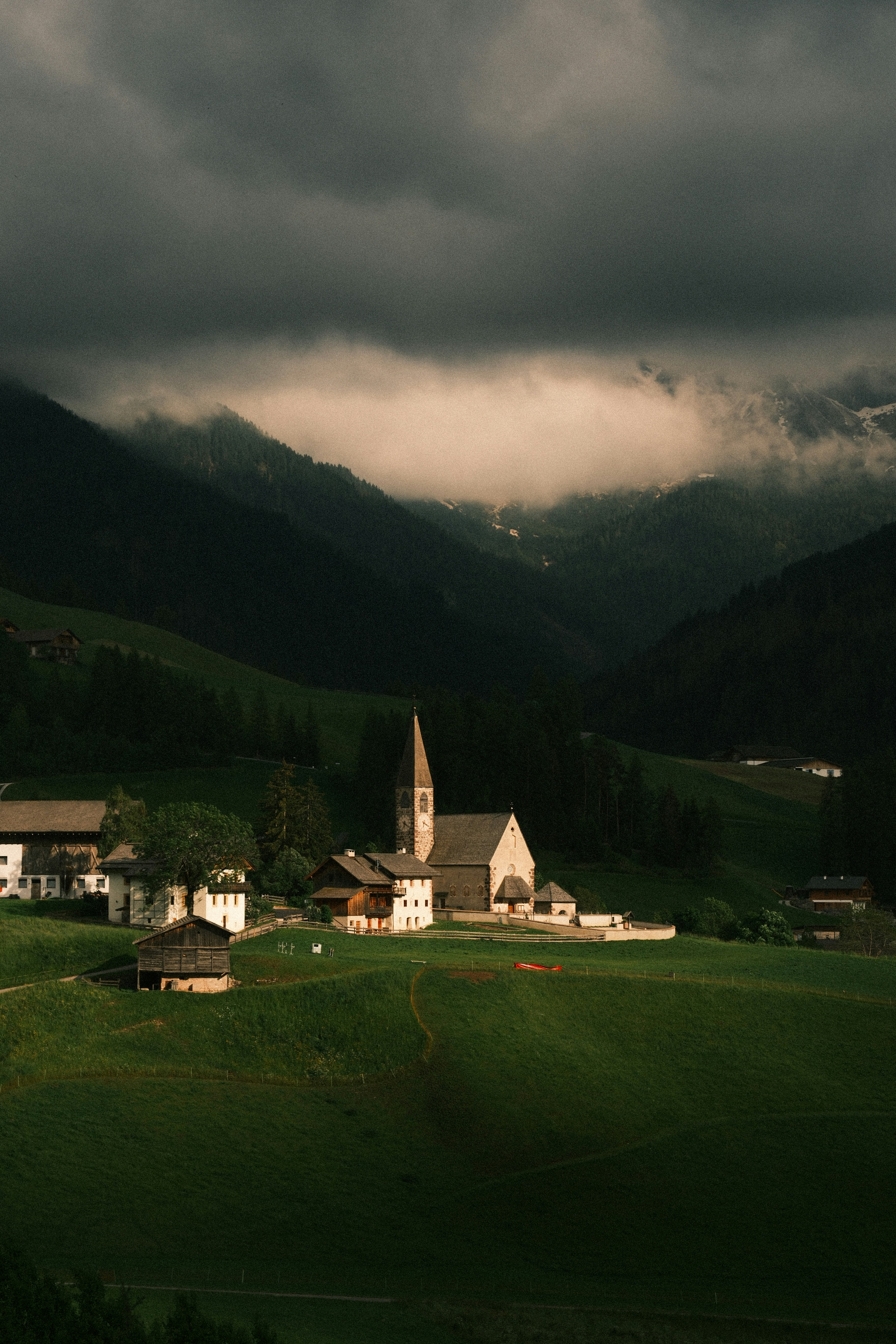 A church sits in a valley surrounded by mountains.
