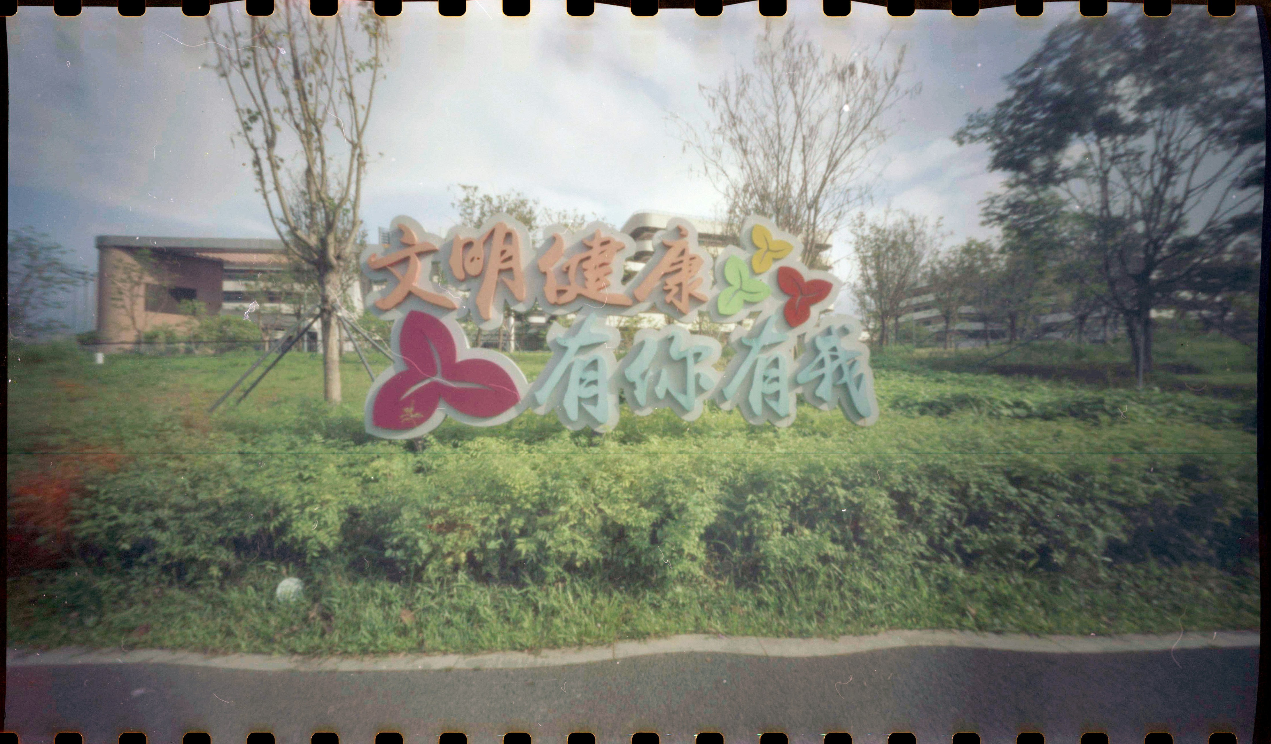 A sign stands in front of greenery.