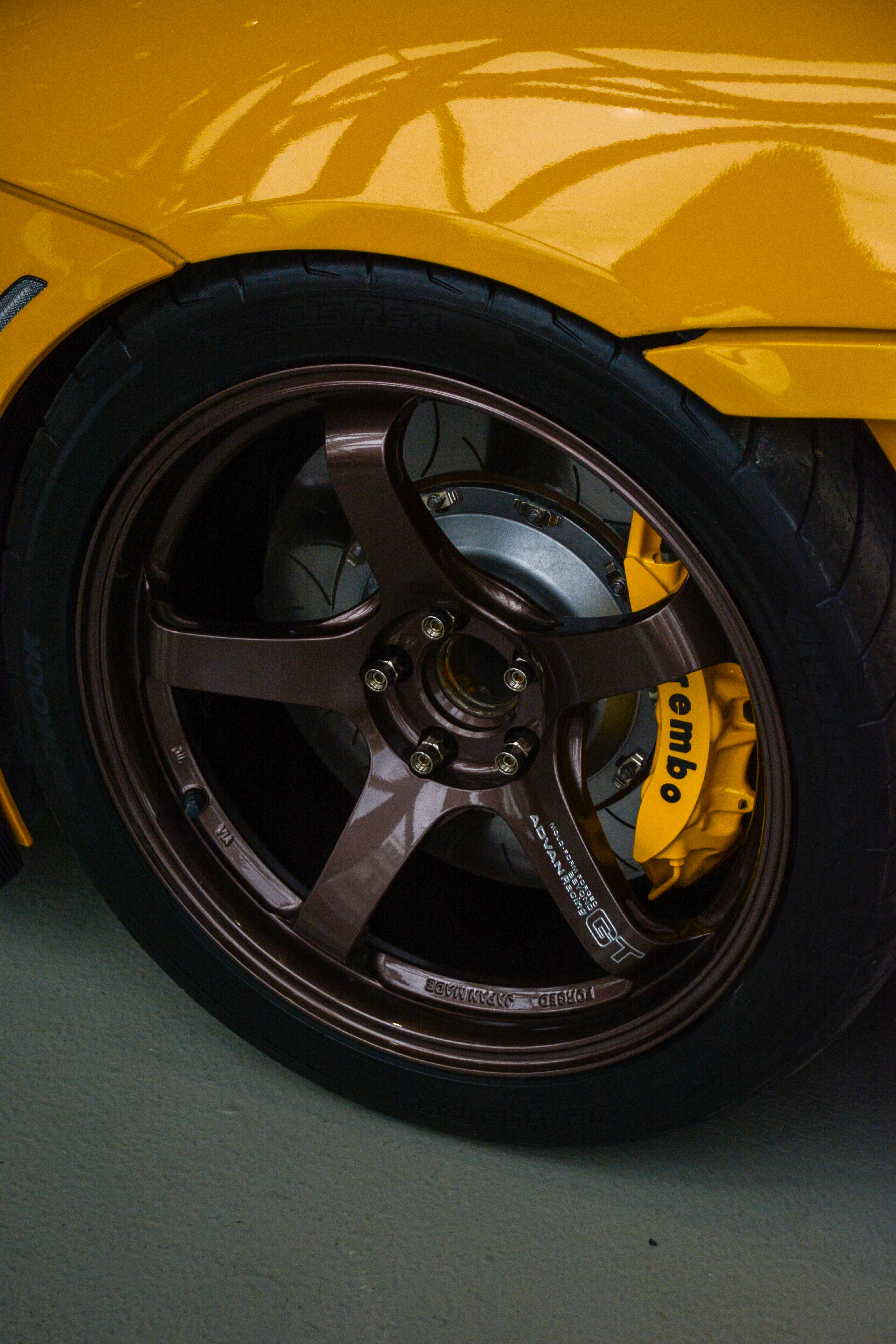 A yellow car's wheel with a brembo brake system.