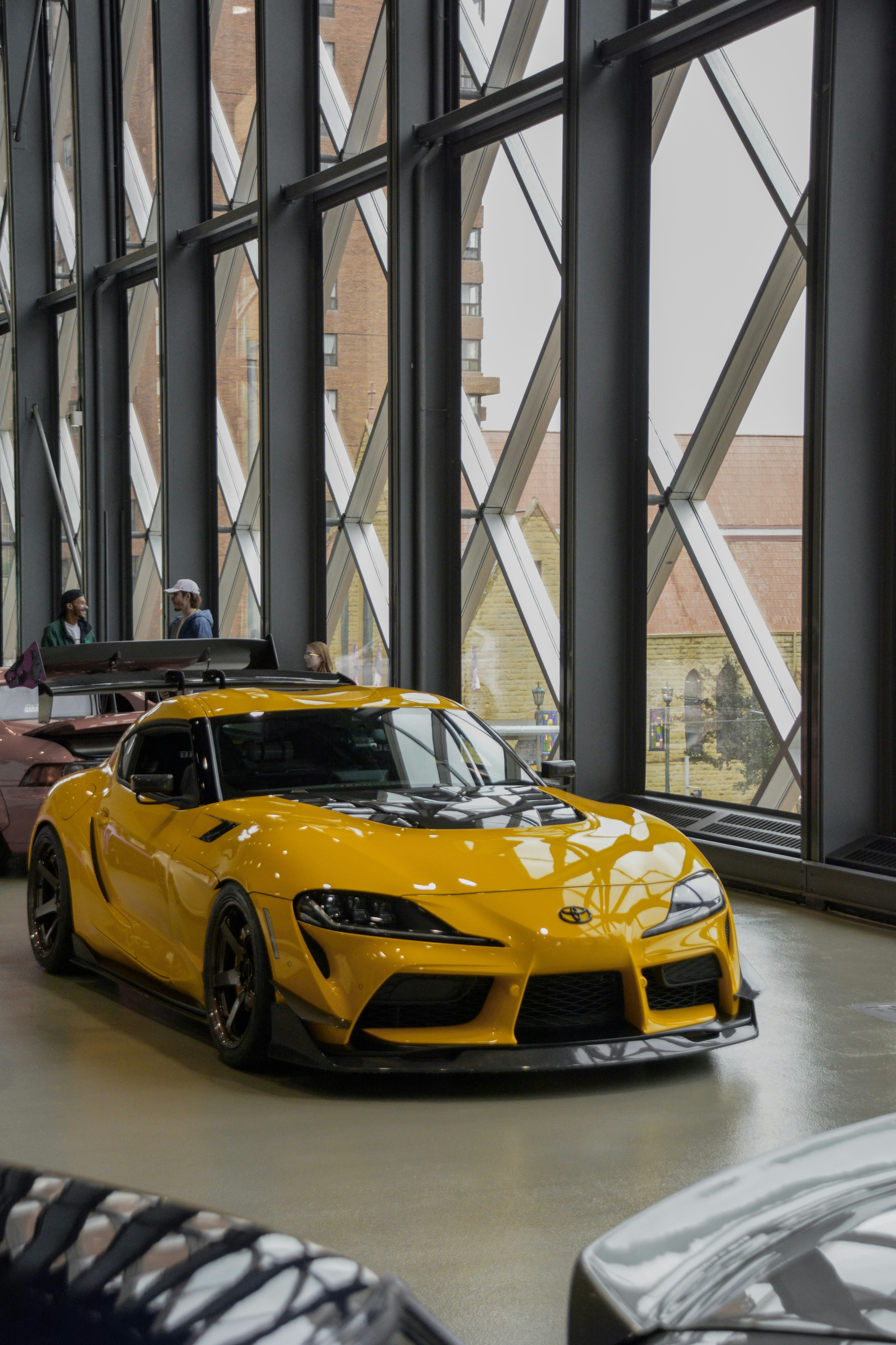 A yellow toyota supra is on display indoors.