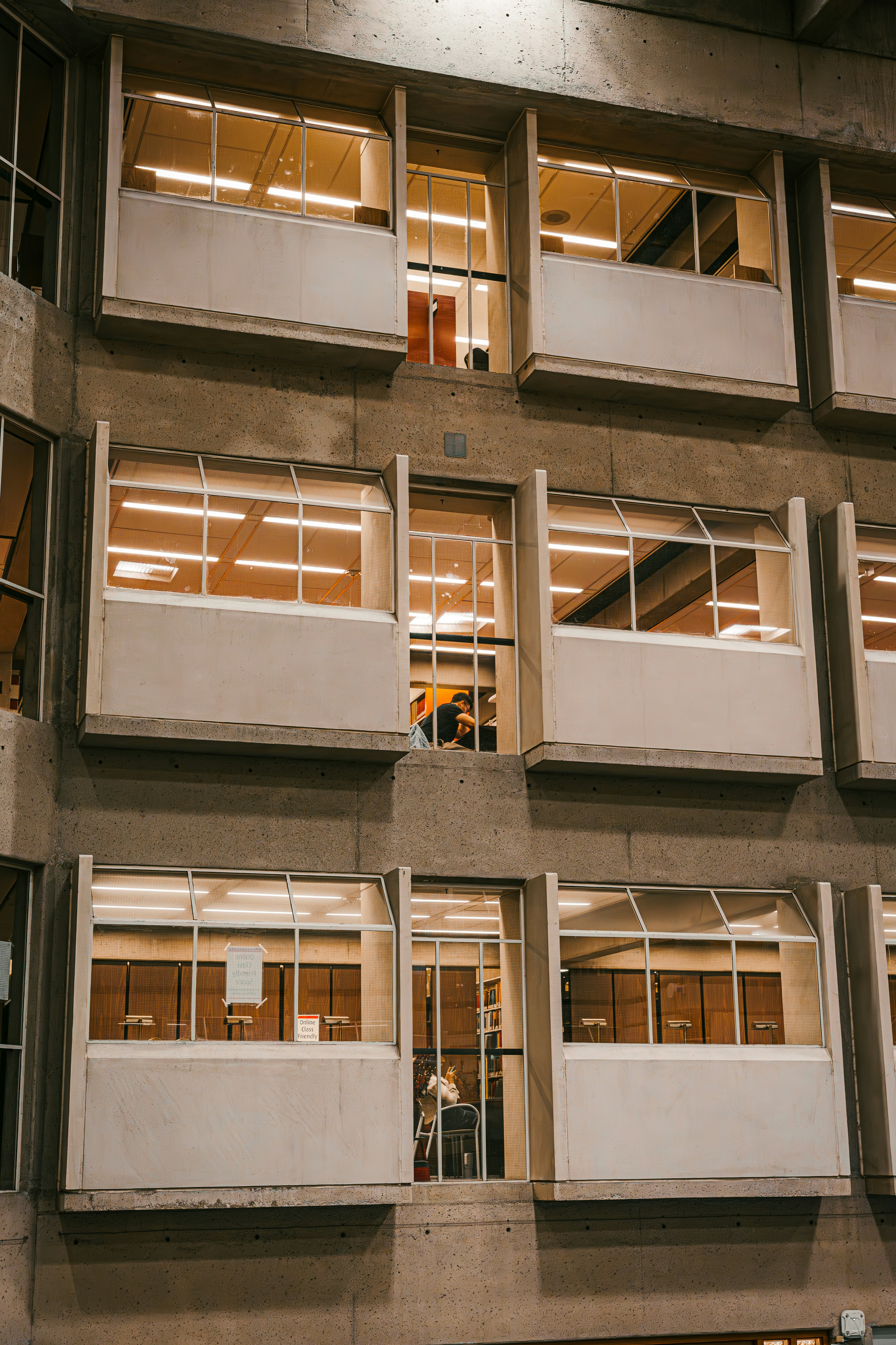 Scott Library at York University | Office windows reveal workers illuminated indoors at night.