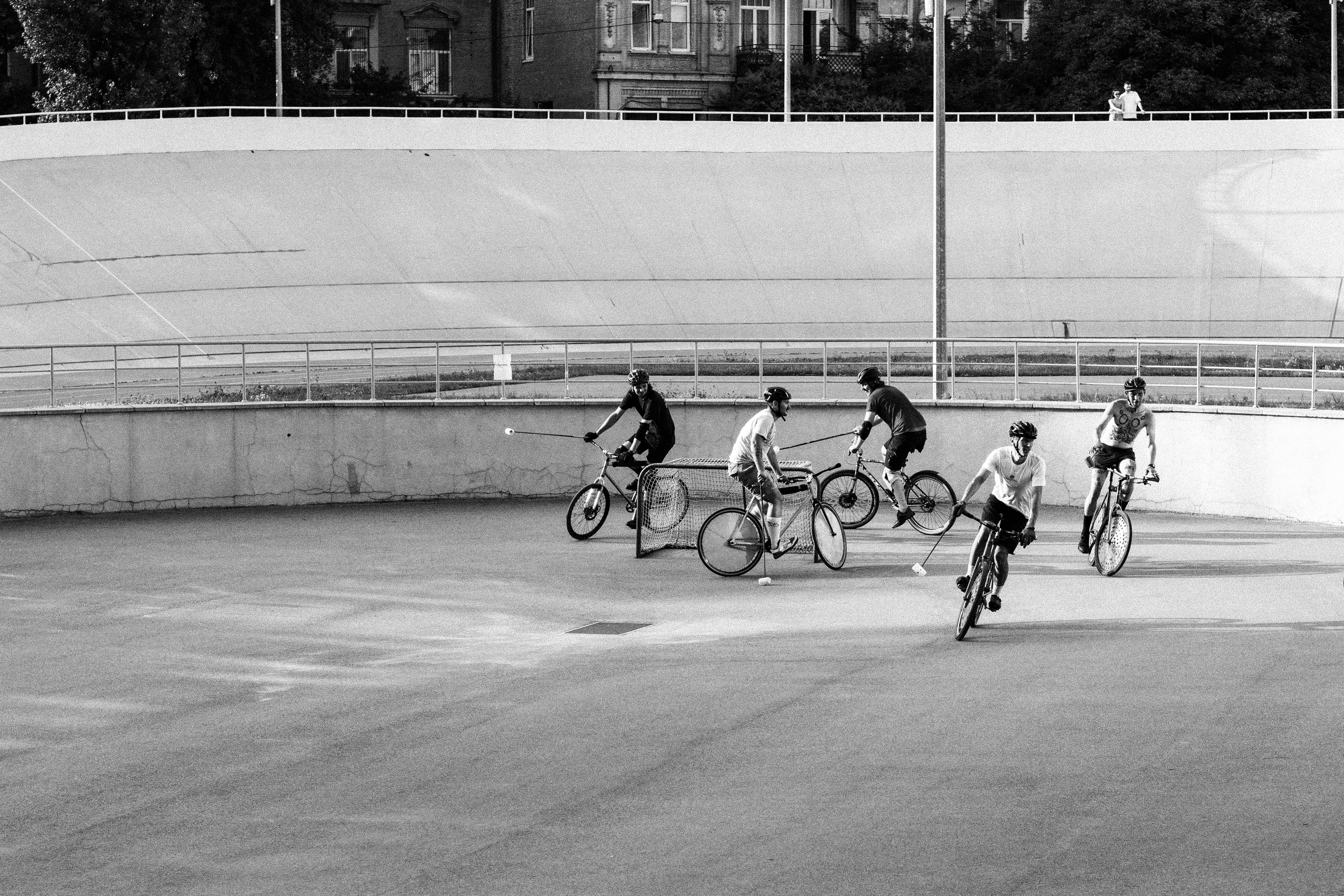 Cyclists maneuvering through a velodrome, showcasing dynamic movement and athleticism in monochrome tones.