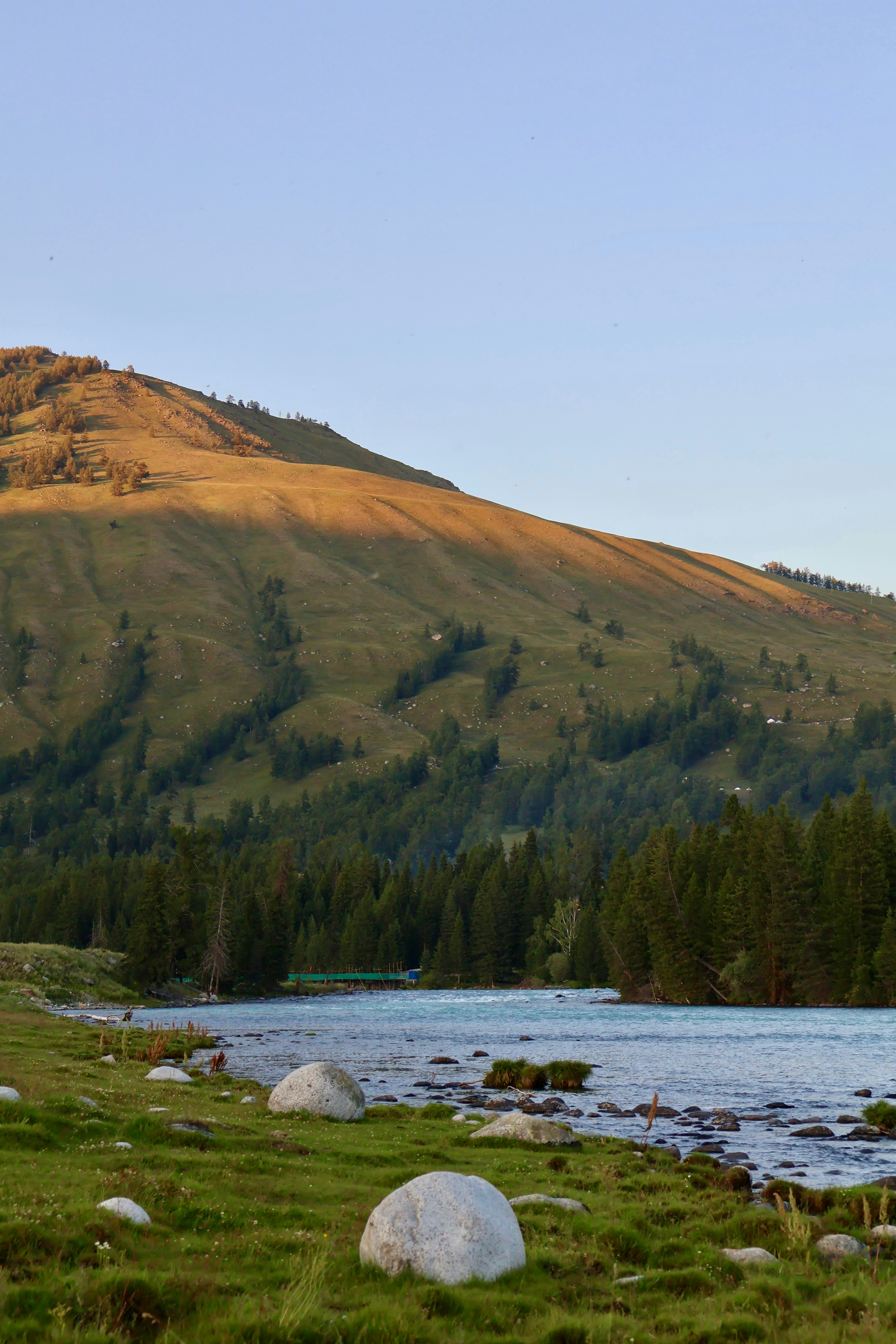 A river flows near green mountain ranges.
