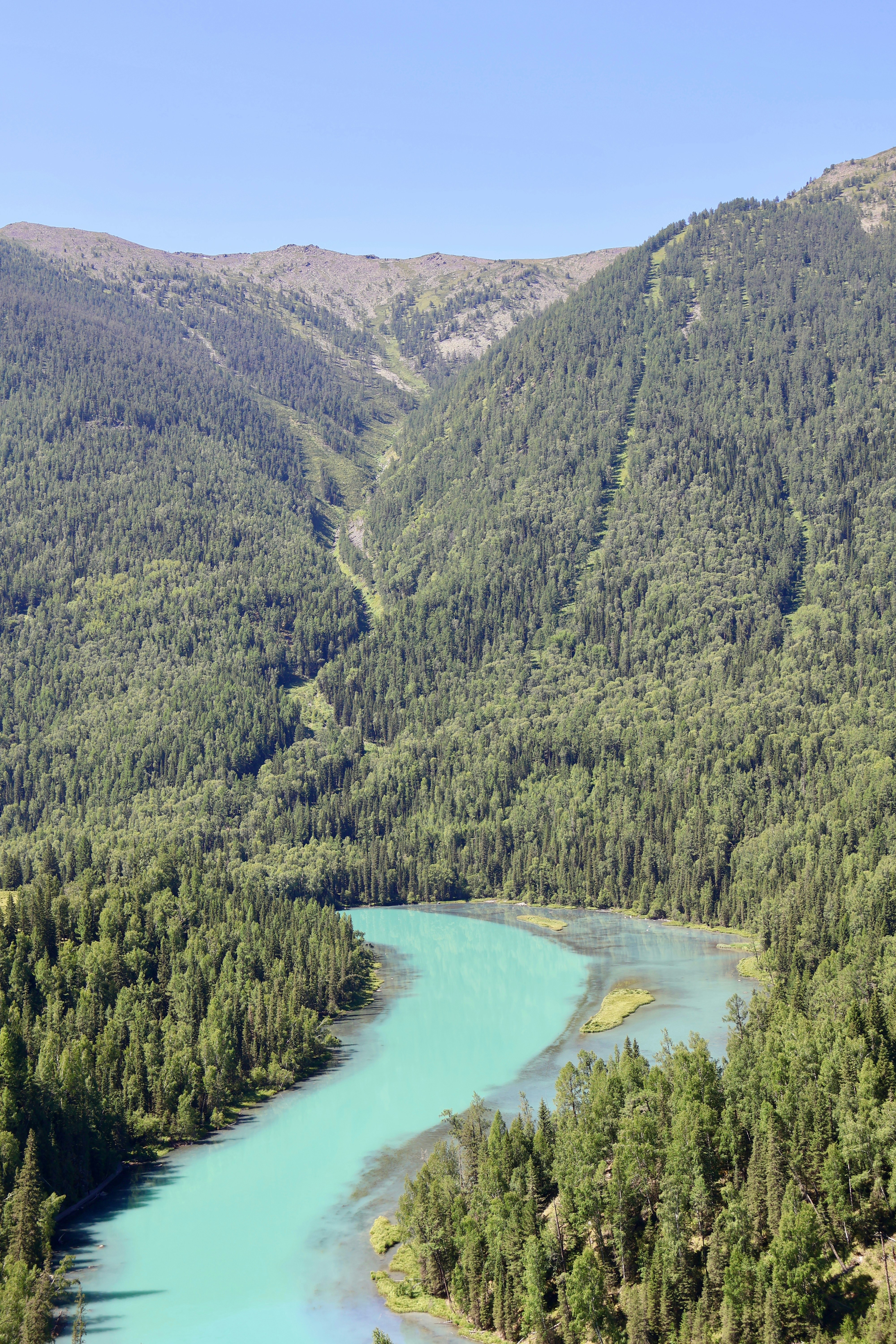 A turquoise river flows through lush green mountains.
