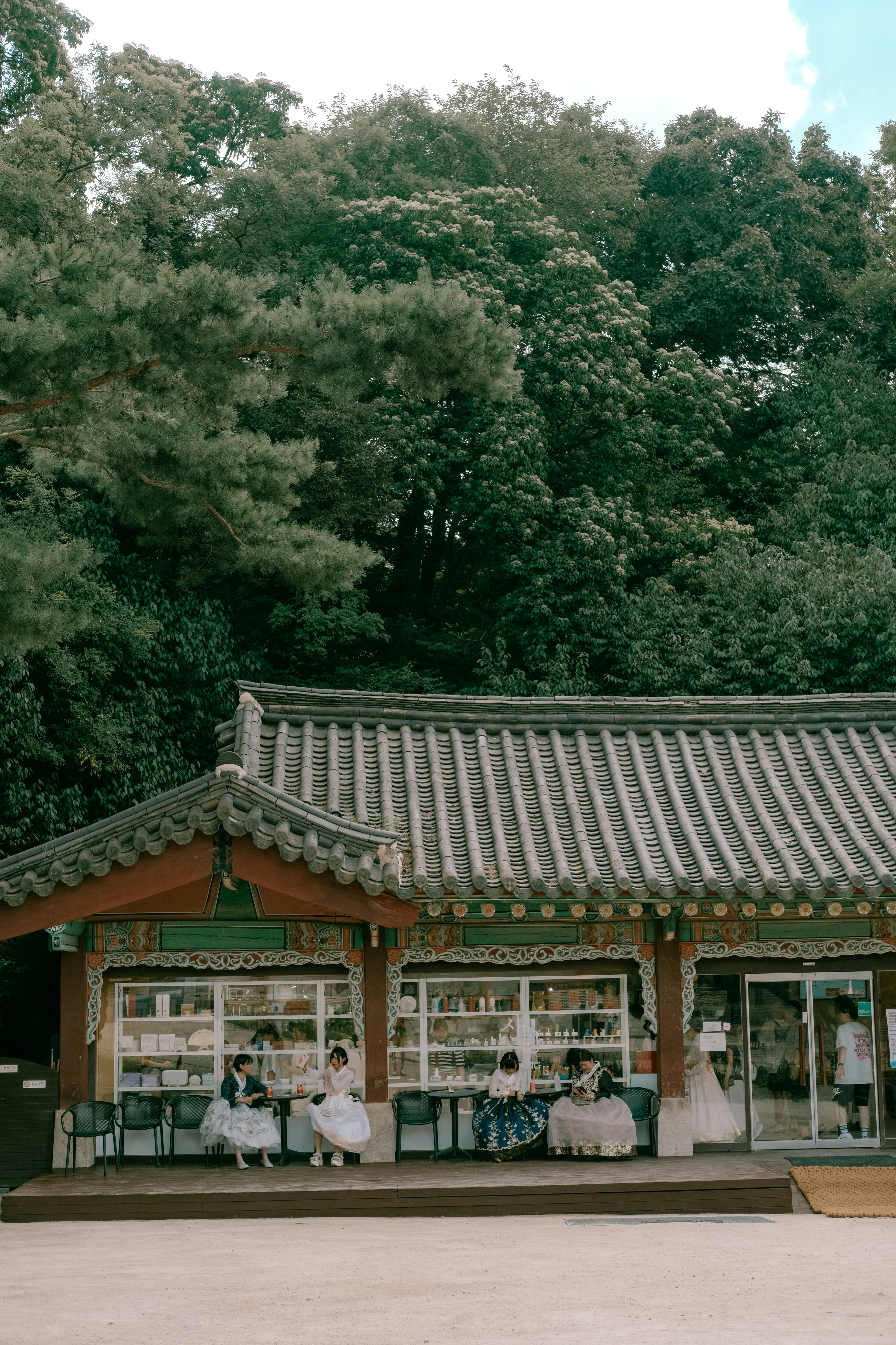 People in traditional korean clothing sit outside.