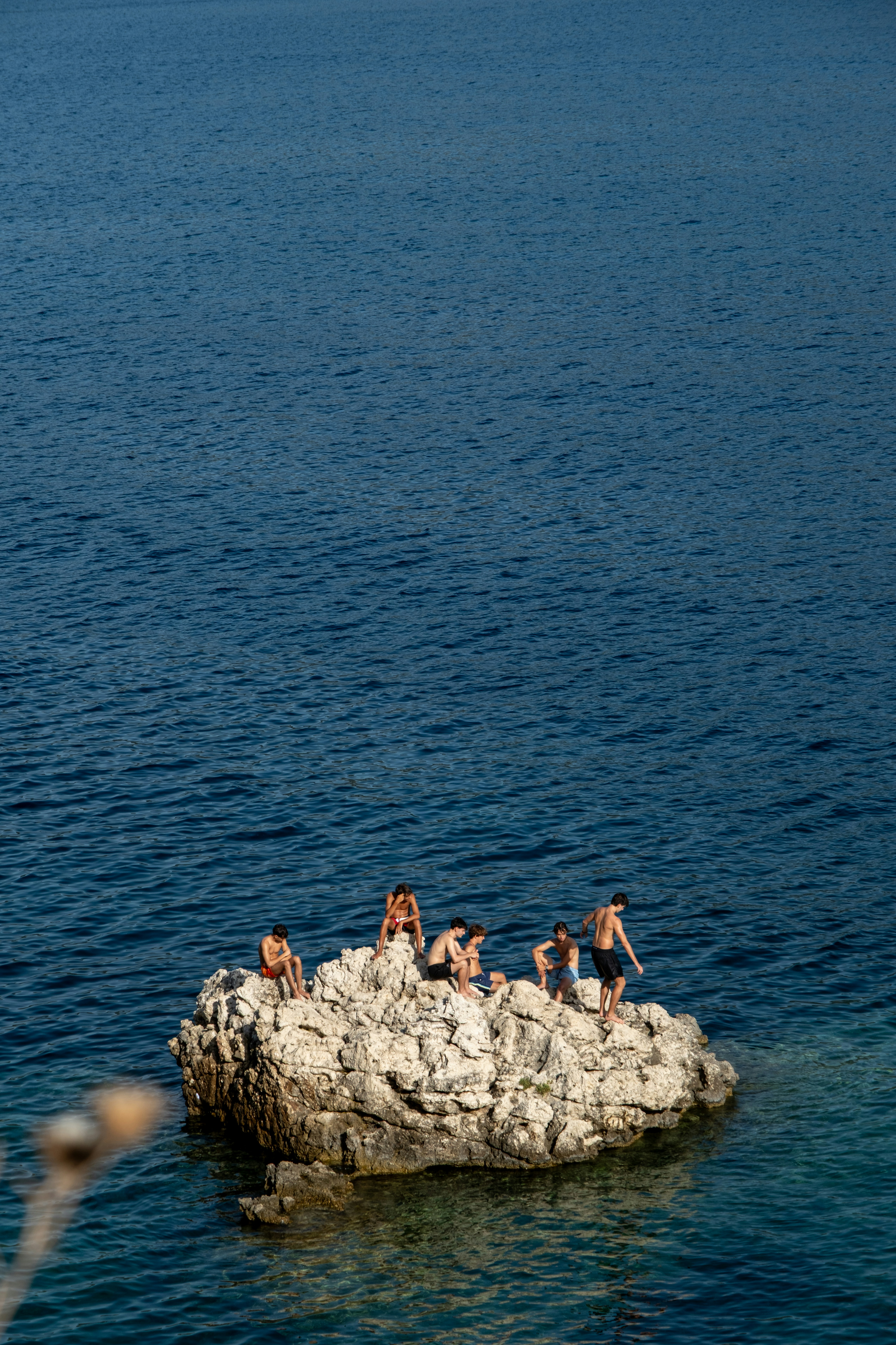 People are jumping off a rock into the sea. photo – Free People Image ...