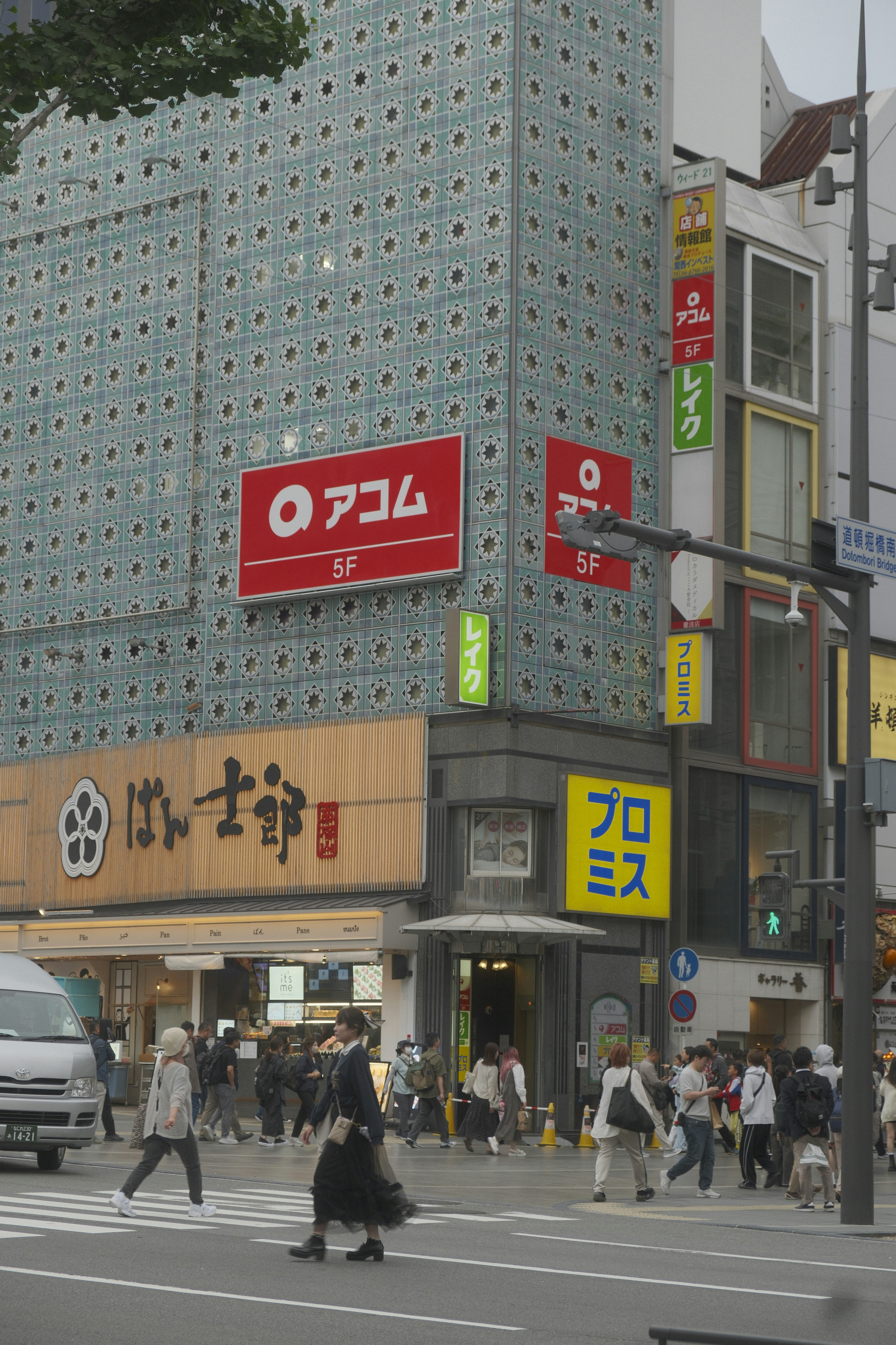 Colorful storefronts and bustling pedestrians create a vibrant urban scene in a busy city intersection.