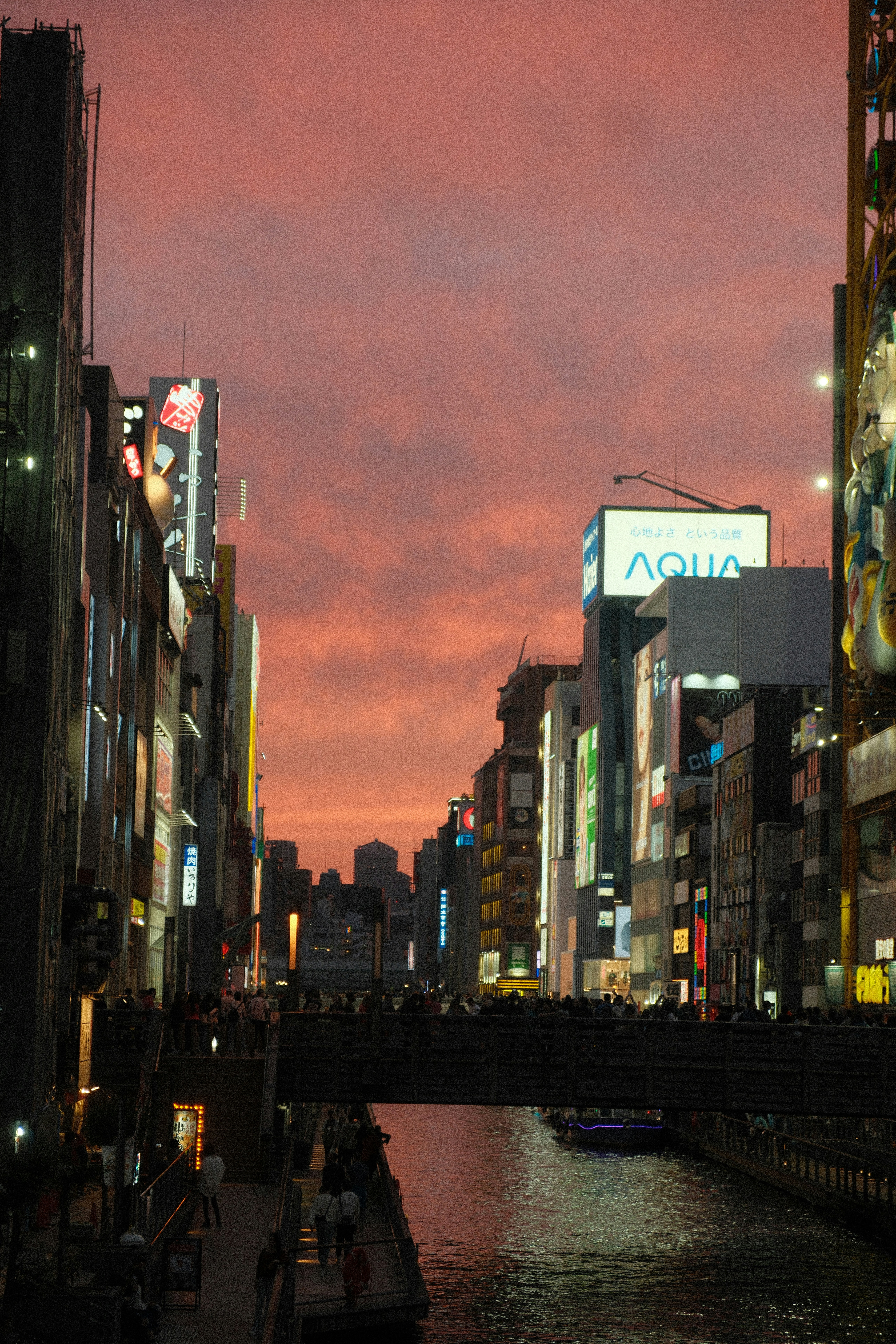 Cityscape with buildings, a bridge, and a sunset.