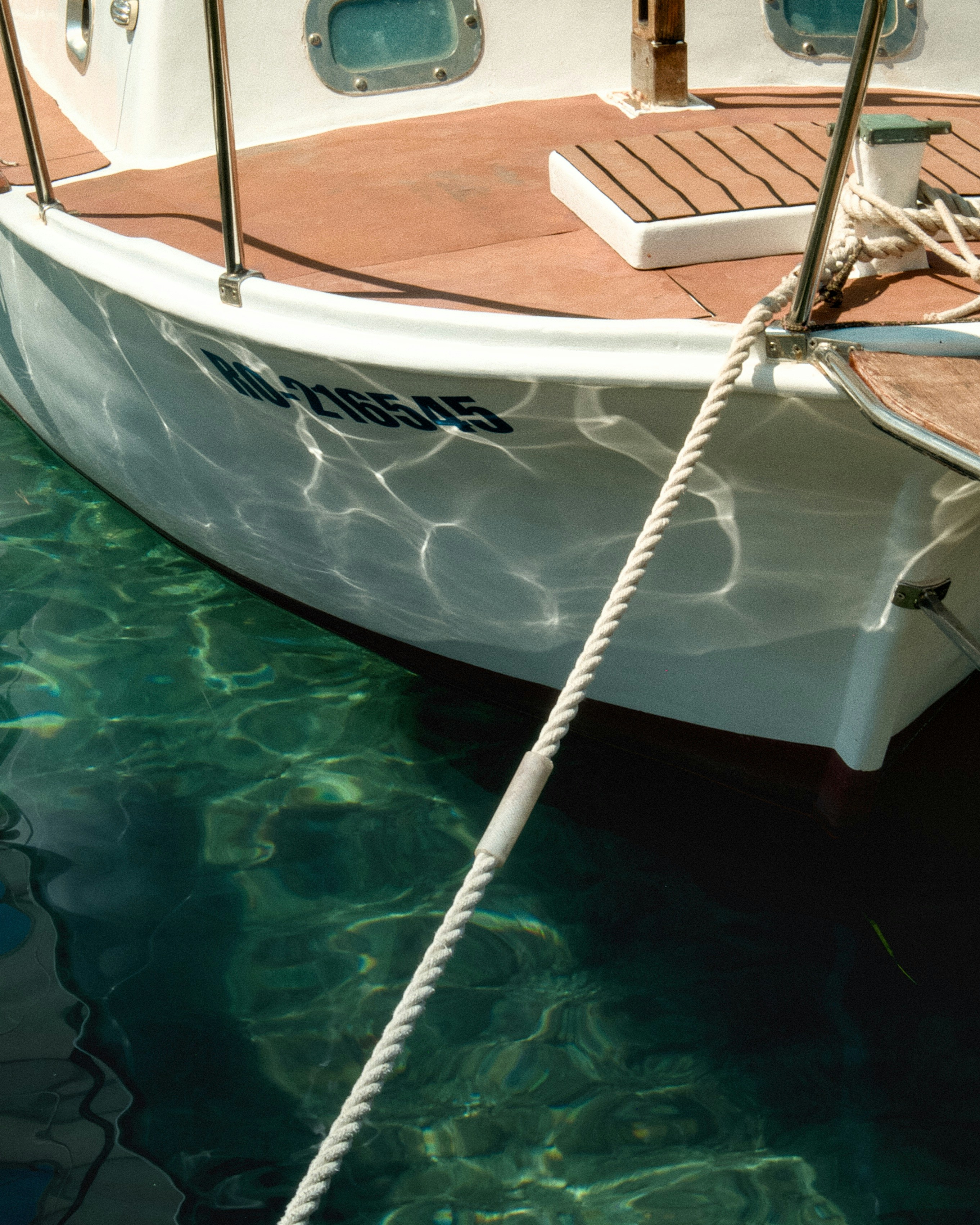 water reflecting back onto a boat | A boat is tied up in crystal clear water.