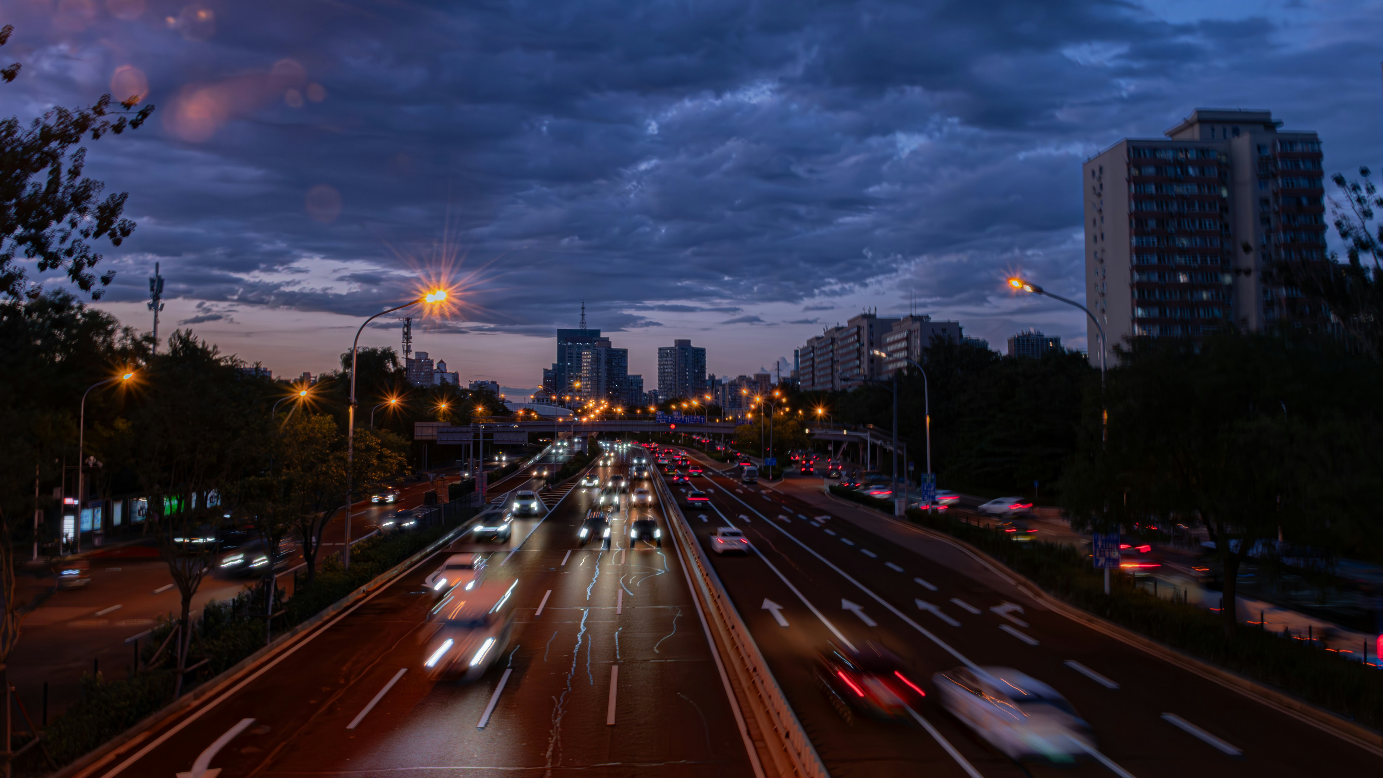 Nighttime traffic moves under a cloudy sky.