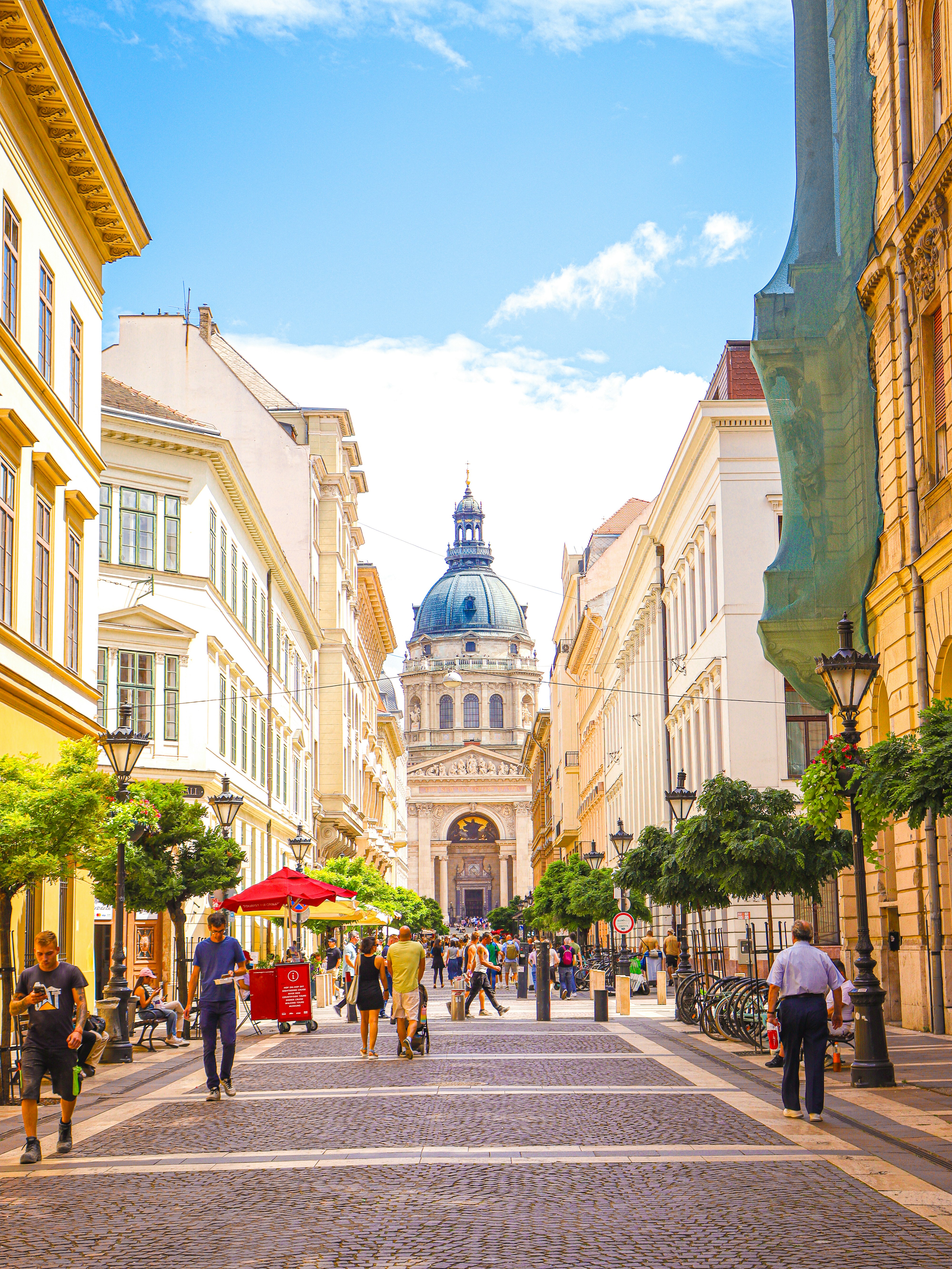 A bustling european street leads to a beautiful cathedral.