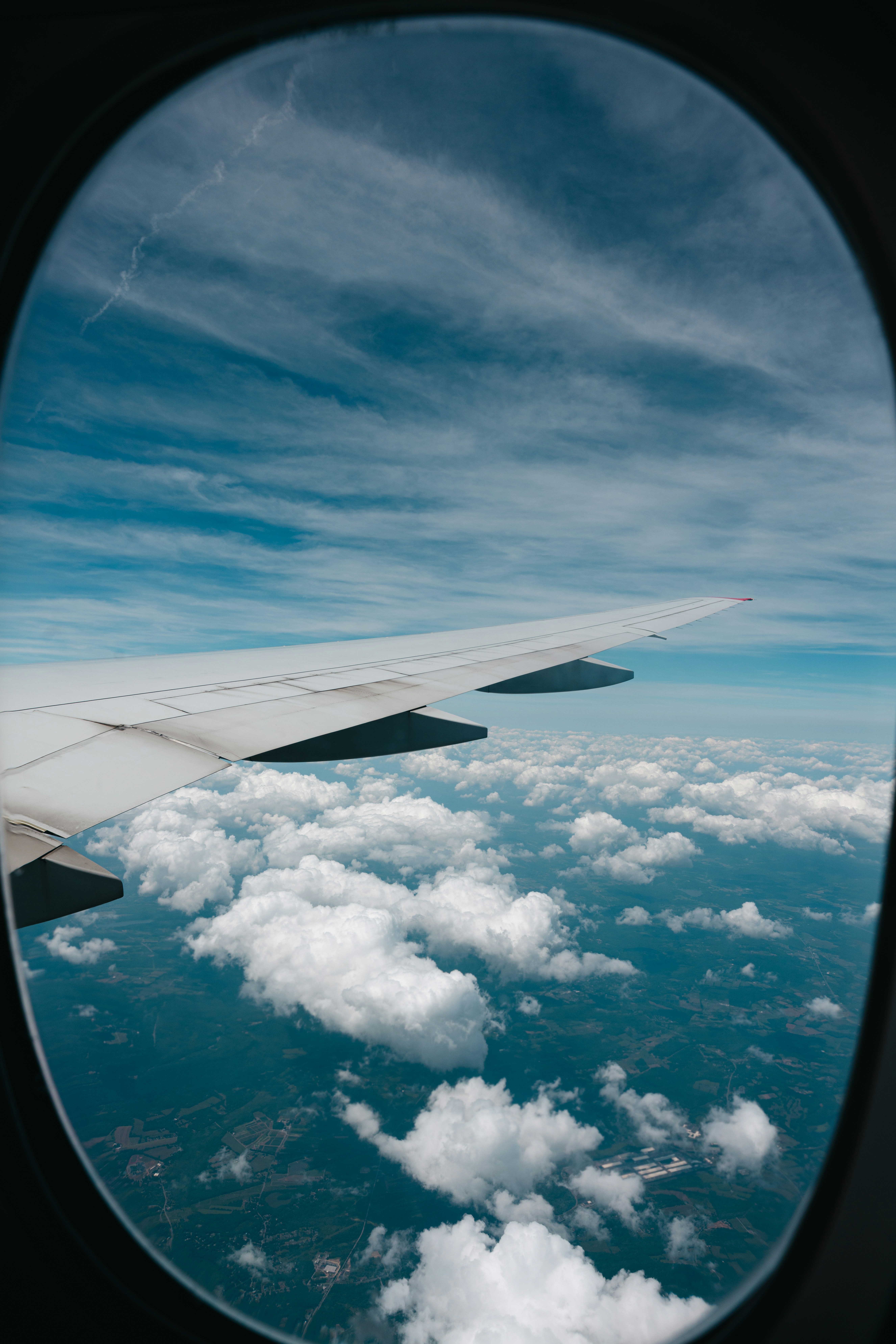 Airplane wing view: clouds and blue sky.