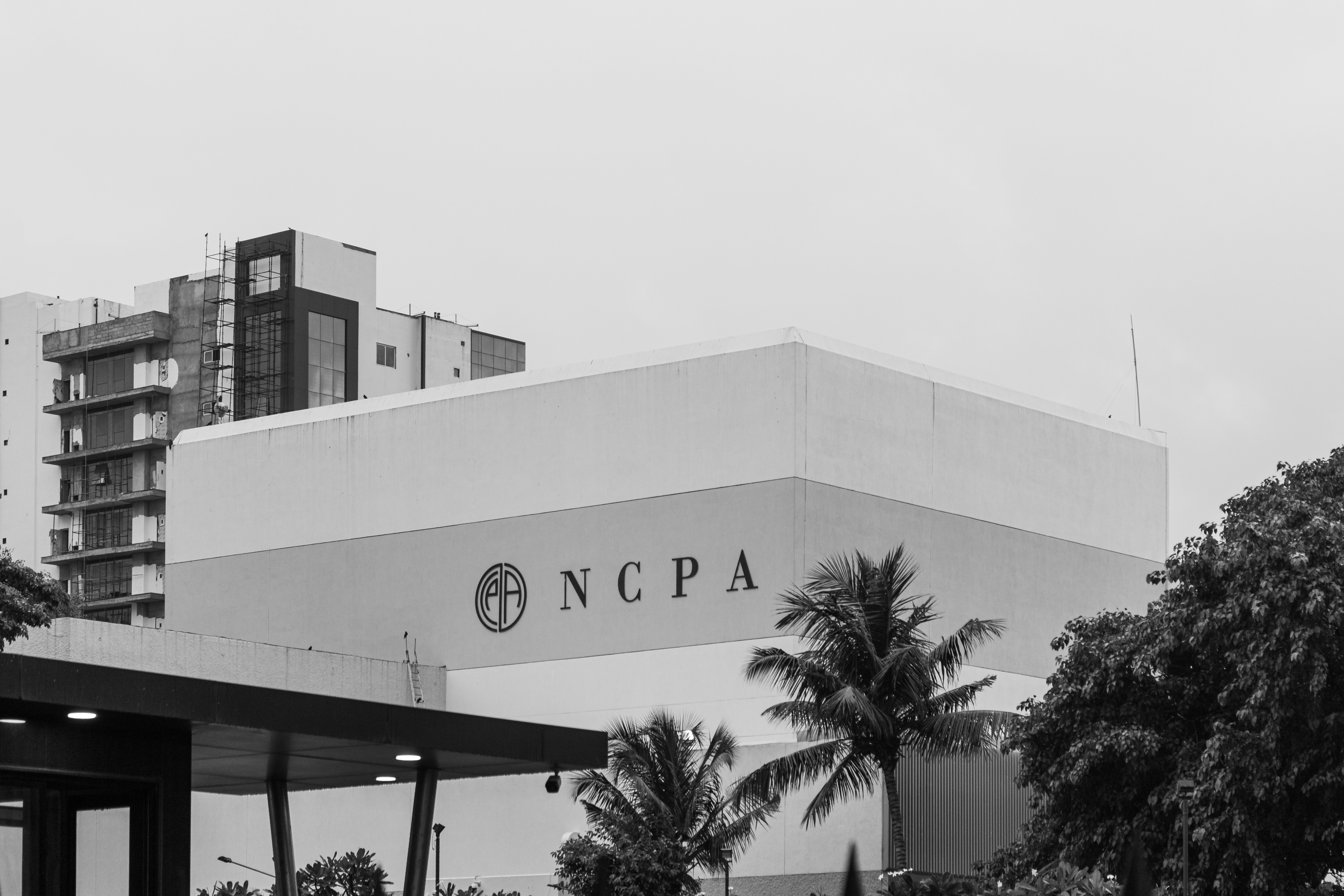 The National Centre for the Performing Arts (NCPA) at Nariman Point in Mumbai, a prominent cultural landmark on India’s western coastline. Known for its distinct architecture and role in promoting performing arts, the NCPA stands at the edge of the Arabian Sea, blending urban design with scenic surroundings. The photograph showcases the building’s clean lines, geometric form, and the calm atmosphere of South Mumbai. | The ncpa building is shown on a cloudy day.