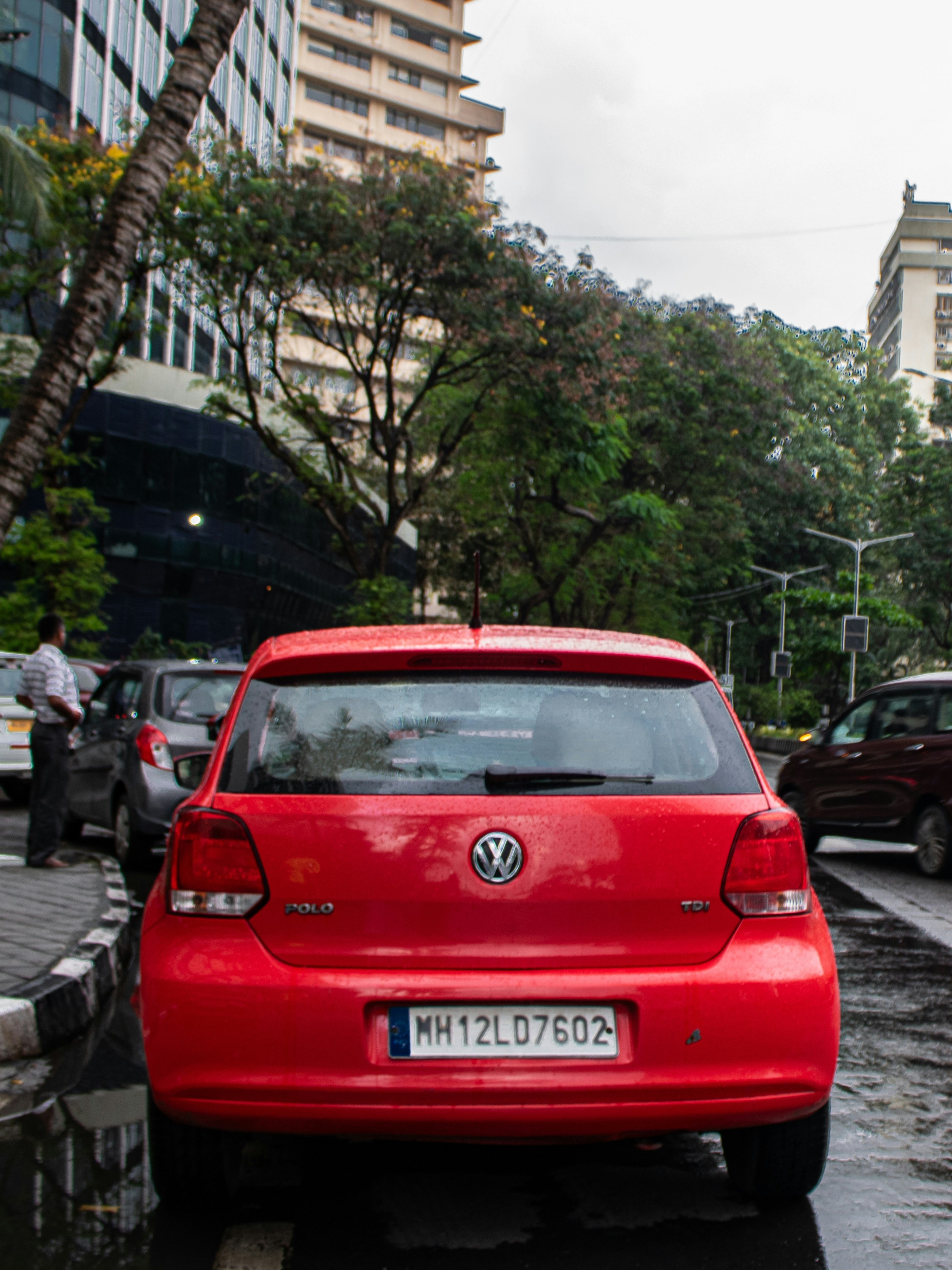 Red Volkswagen Polo TDI is parked on the street at Nariman Point, Mumbai, India. | A red volkswagen car parked on a wet street.