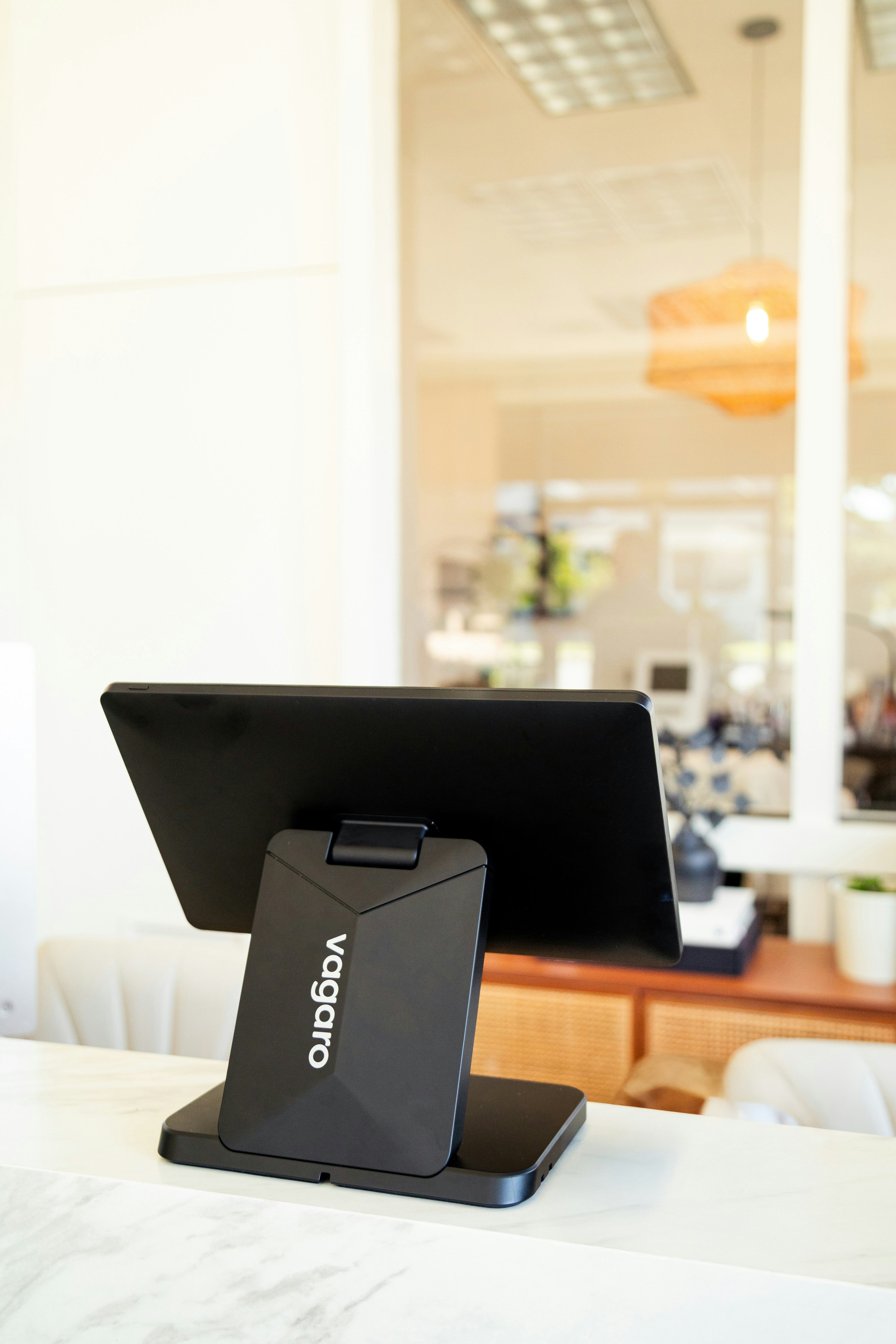 Inside the clean white interior of the salon, the Vagaro PayPro sits at the front desk with beautiful natural light. | A vagaro point-of-sale system sits on a counter.
